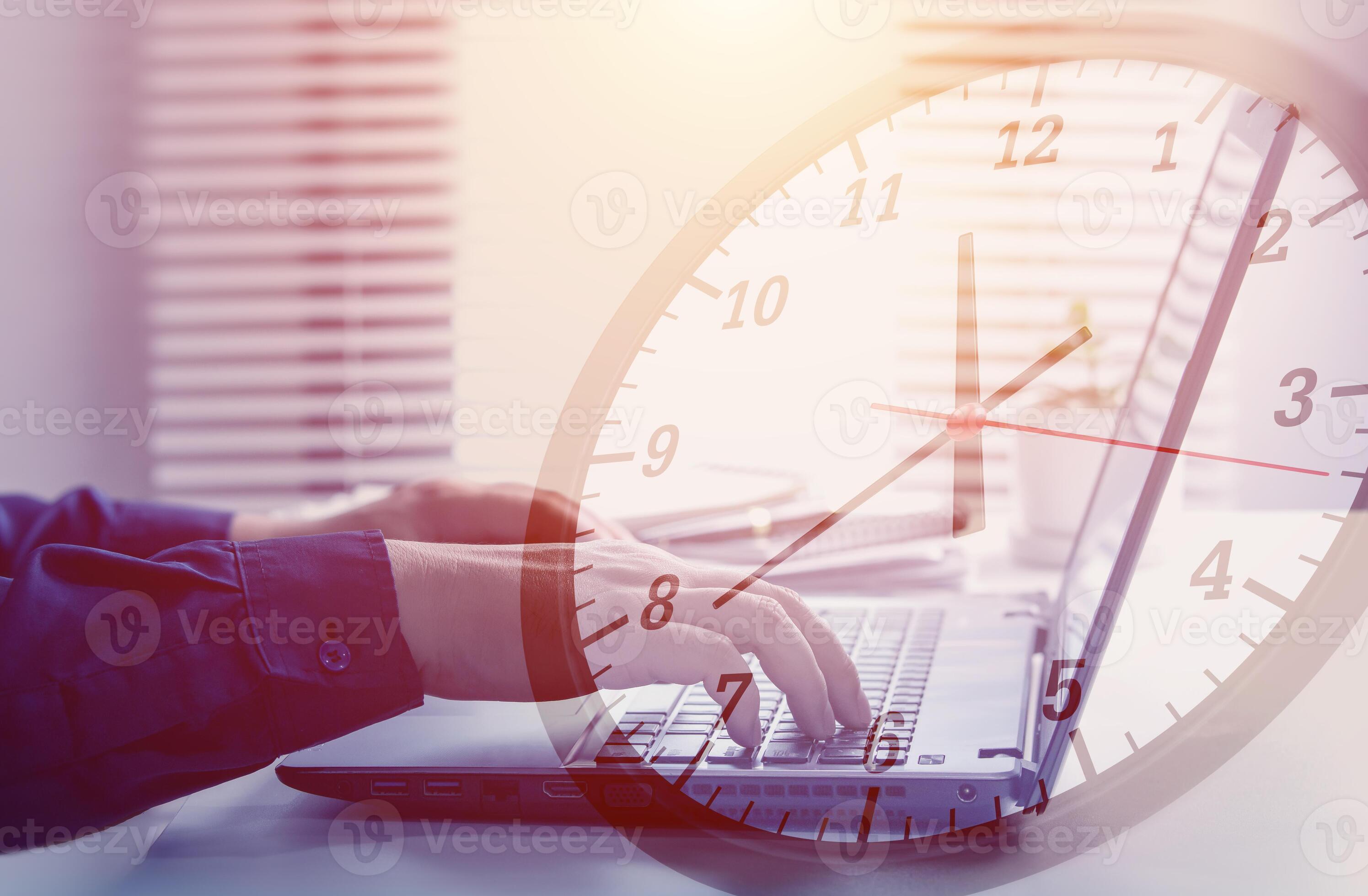 Working hours and working overtime. Close-up view of an employee typing on computer with clock ...