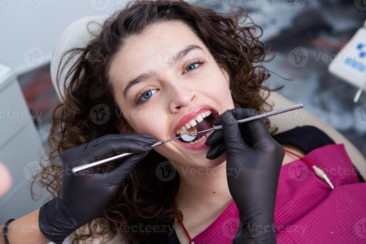 Dentist examining teeth of a young woman patient in a dental clinic. Dentistry concept. Dentist ...