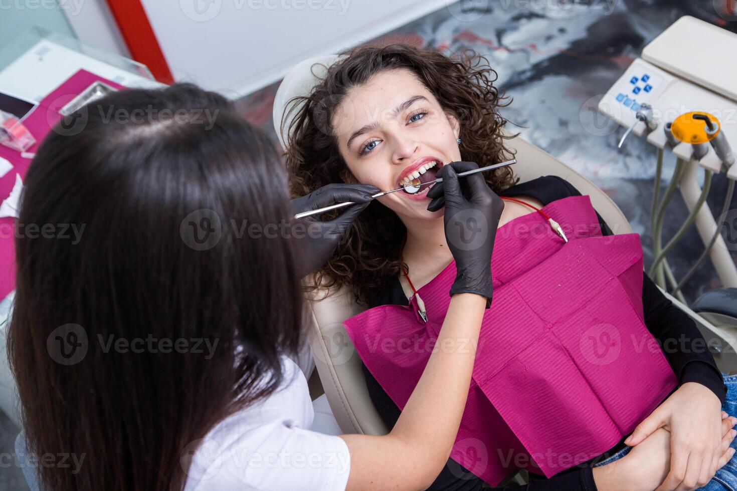 Dentist examining teeth of a young woman patient in a dental clinic. Dentistry concept. Dentist ...