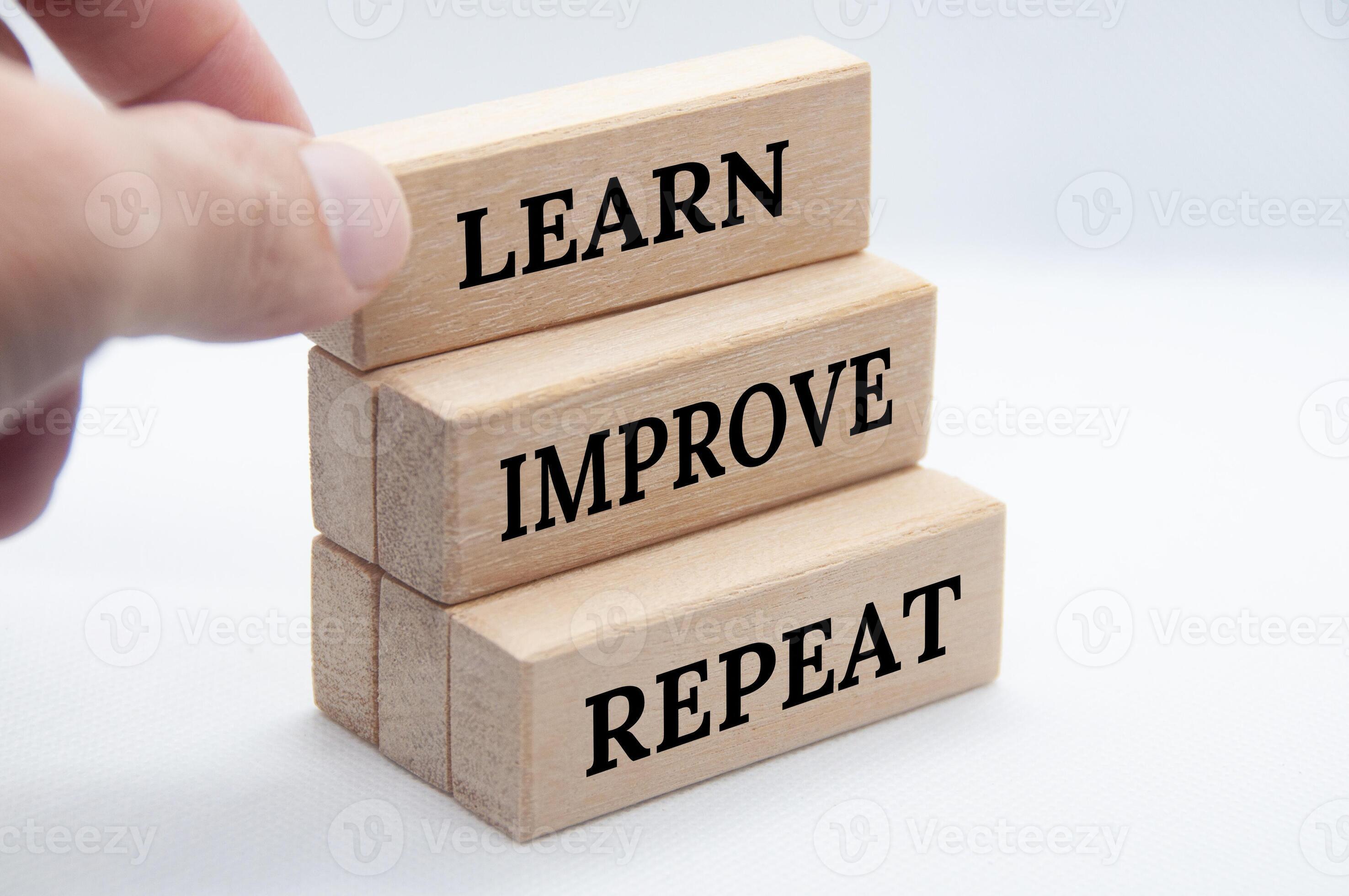 Learn, improve and repeat text on wooden blocks with white cover background. Improvement concept ...
