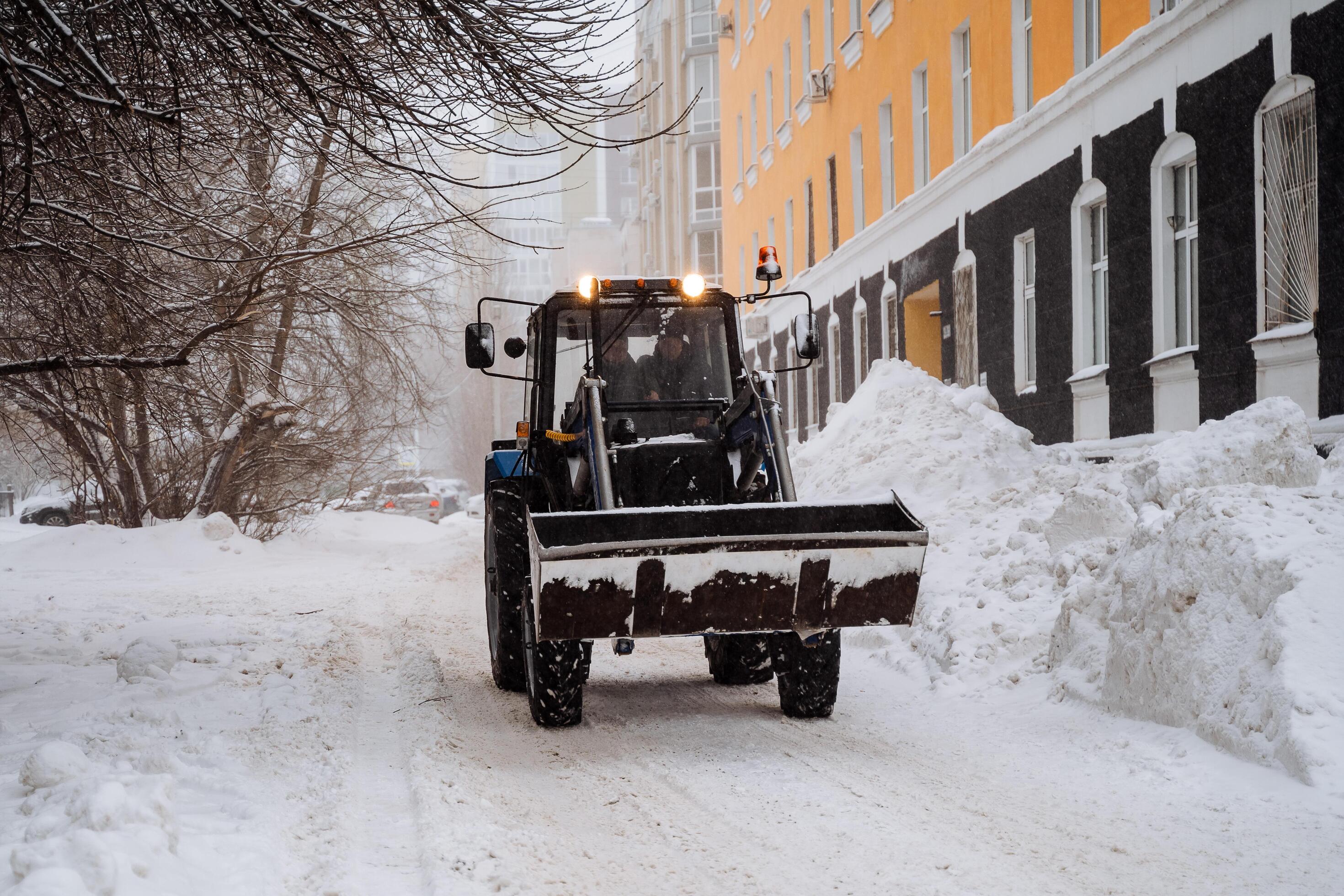 A tractor cleans snow in the city. Clearing the street of snow after a snowstorm. Ufa Russia ...