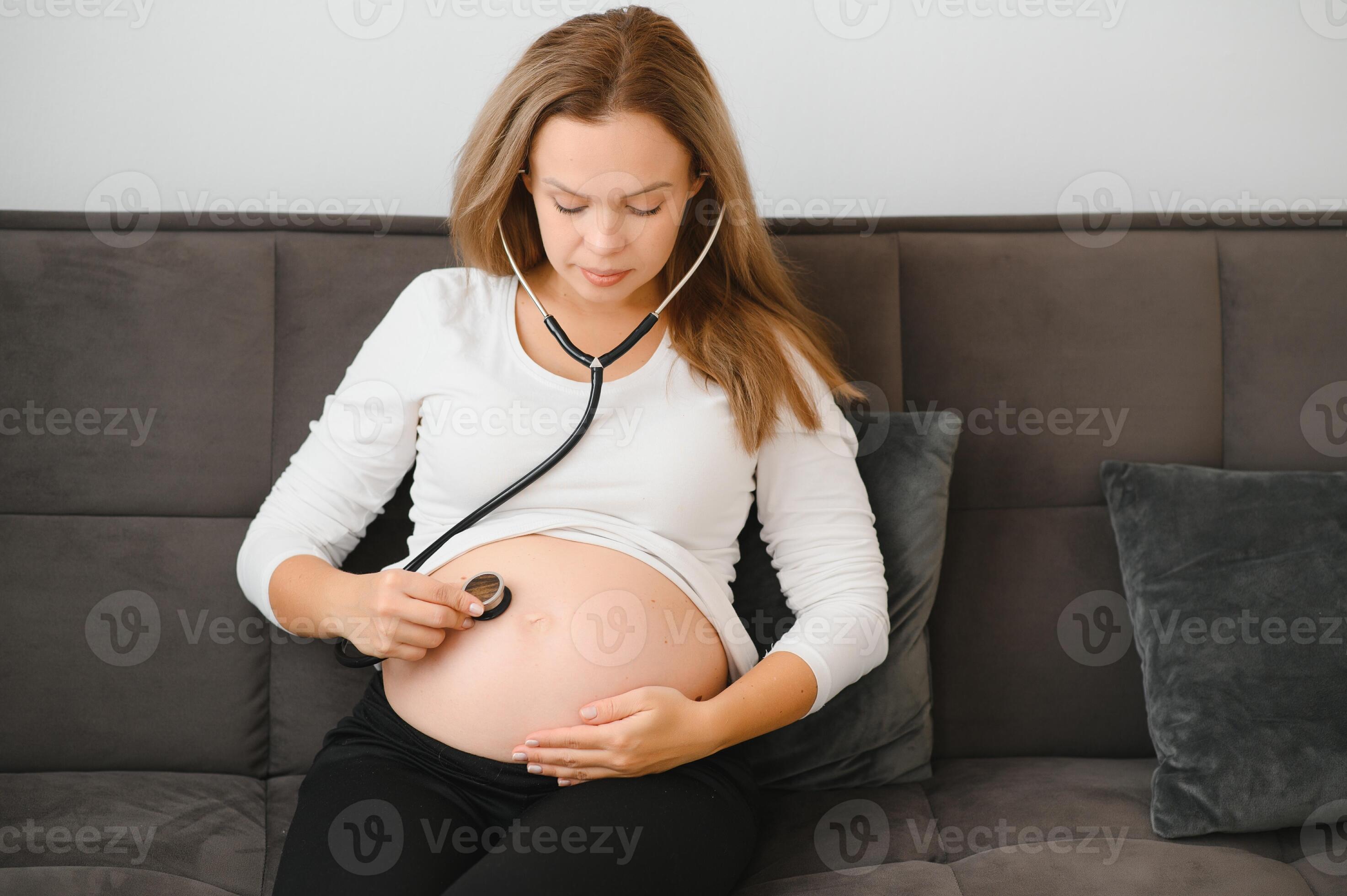 The mother is using stethoscope the doctor listens to the sound of the baby in the stomach ...