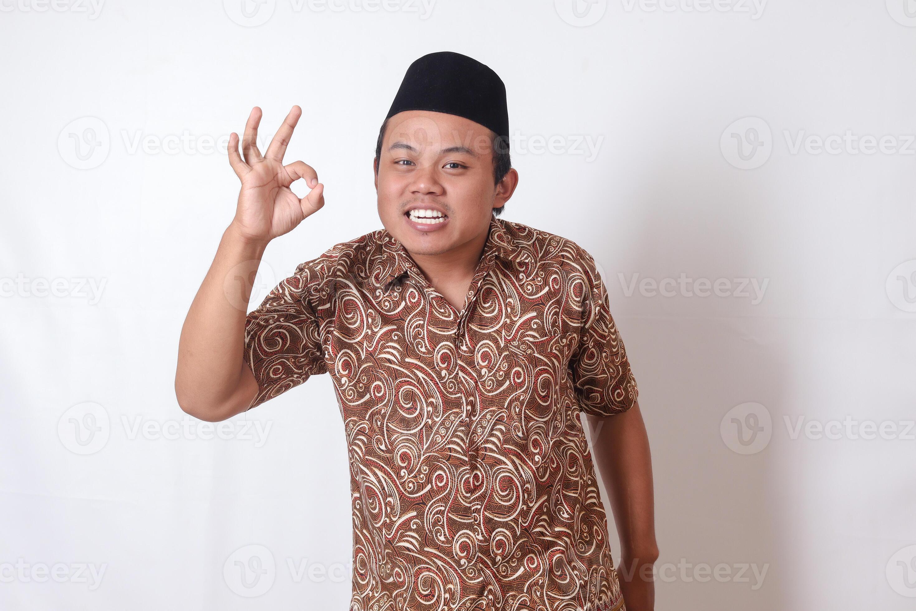 Portrait of excited Asian man wearing batik shirt and songkok showing ...