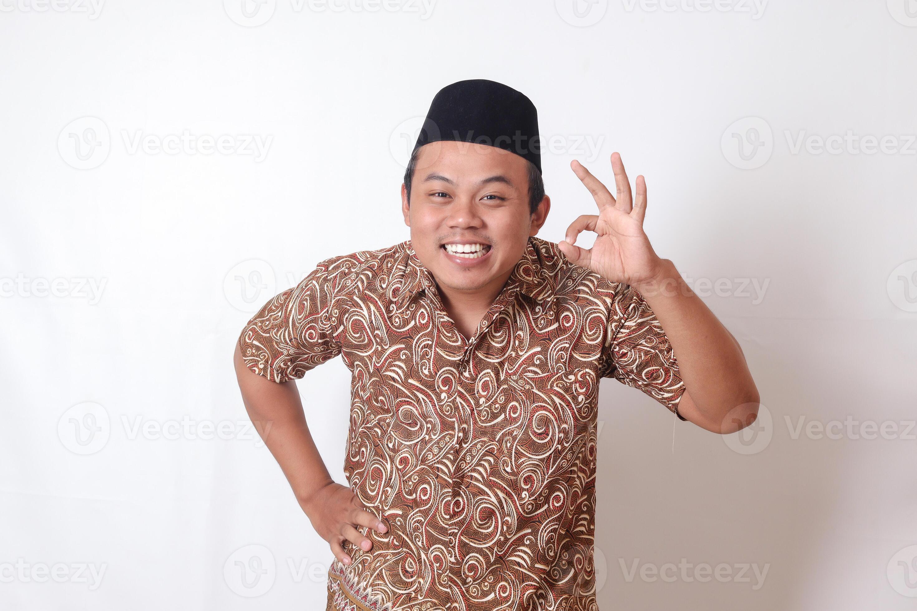 Portrait of excited Asian man wearing batik shirt and songkok showing ...