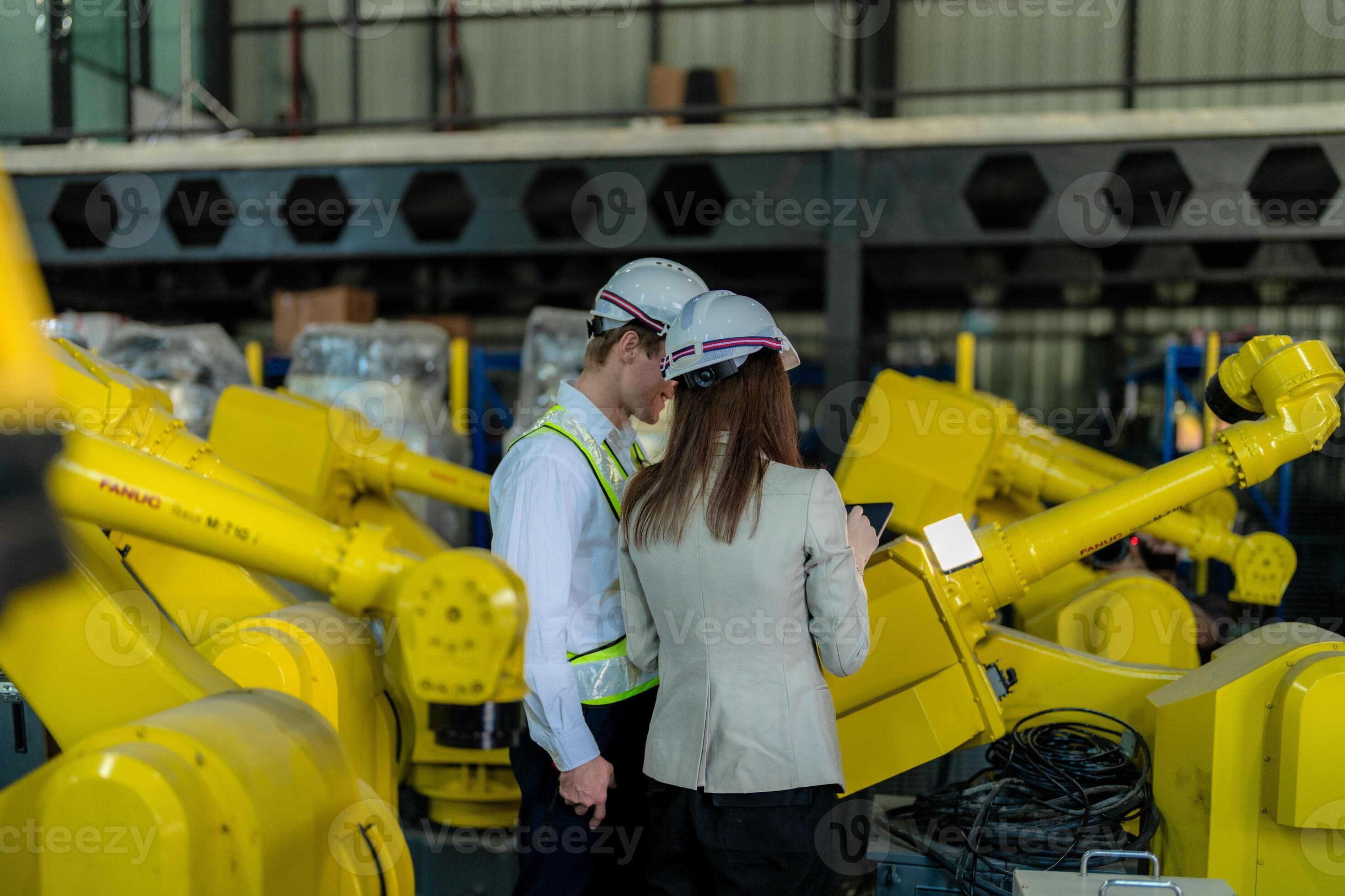 Factory engineers inspecting on machine with smart tablet. Worker works ...