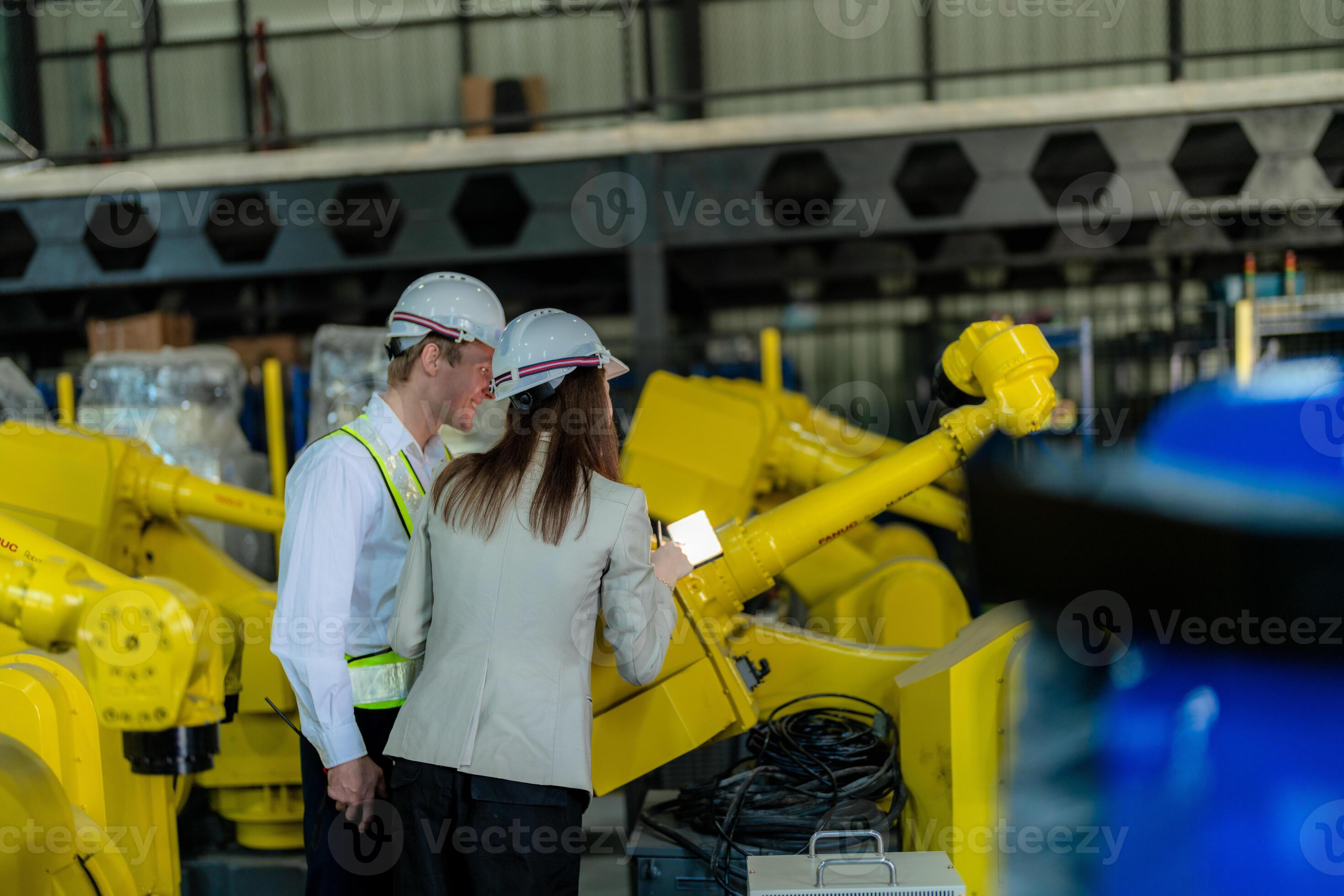 Factory engineers inspecting on machine with smart tablet. Worker works ...