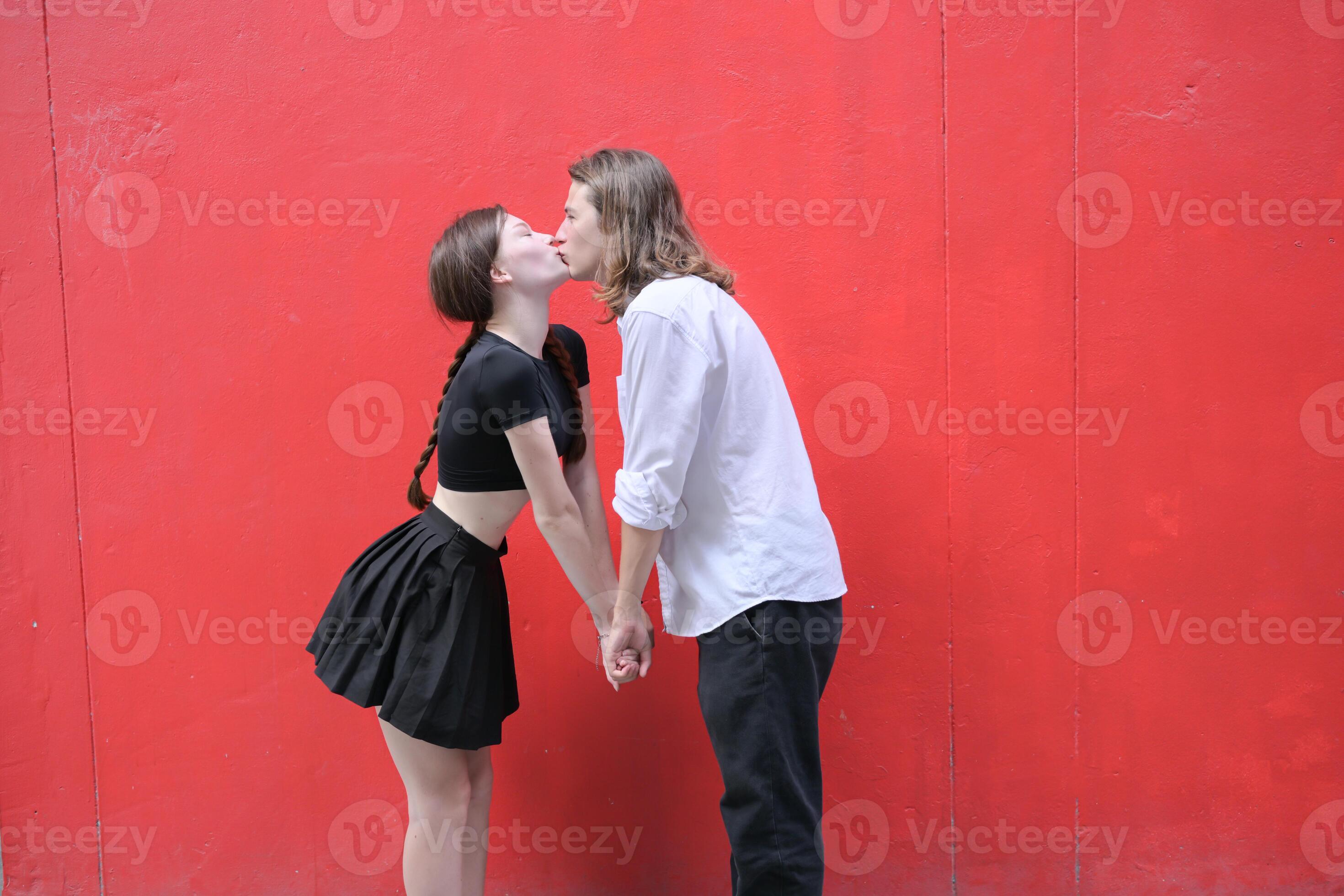 A Couple Is Enjoying A Summer Vacation In The Red Wall Background Happily Showing Their Love To