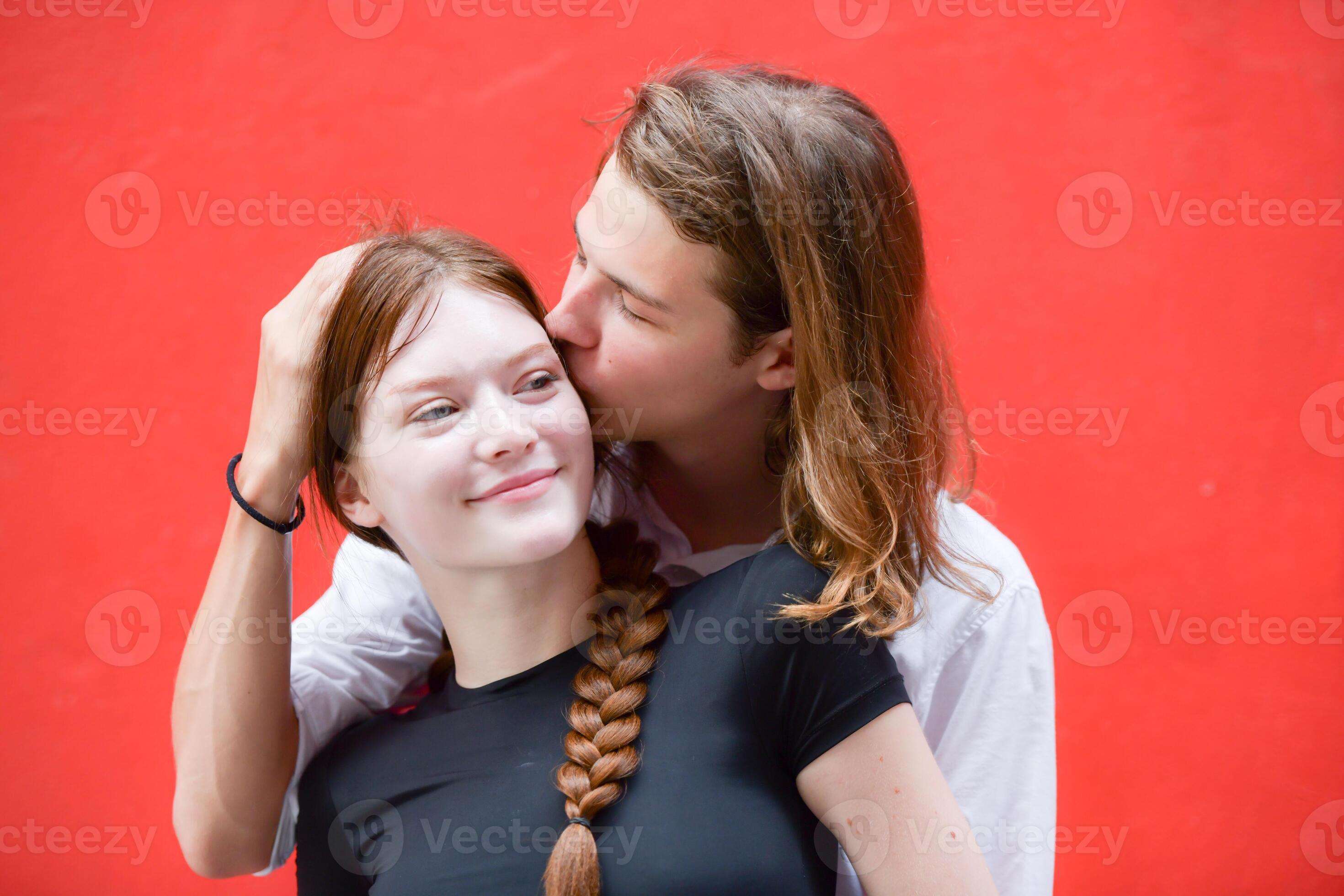 A Couple Is Enjoying A Summer Vacation In The Red Wall Background Happily Showing Their Love To