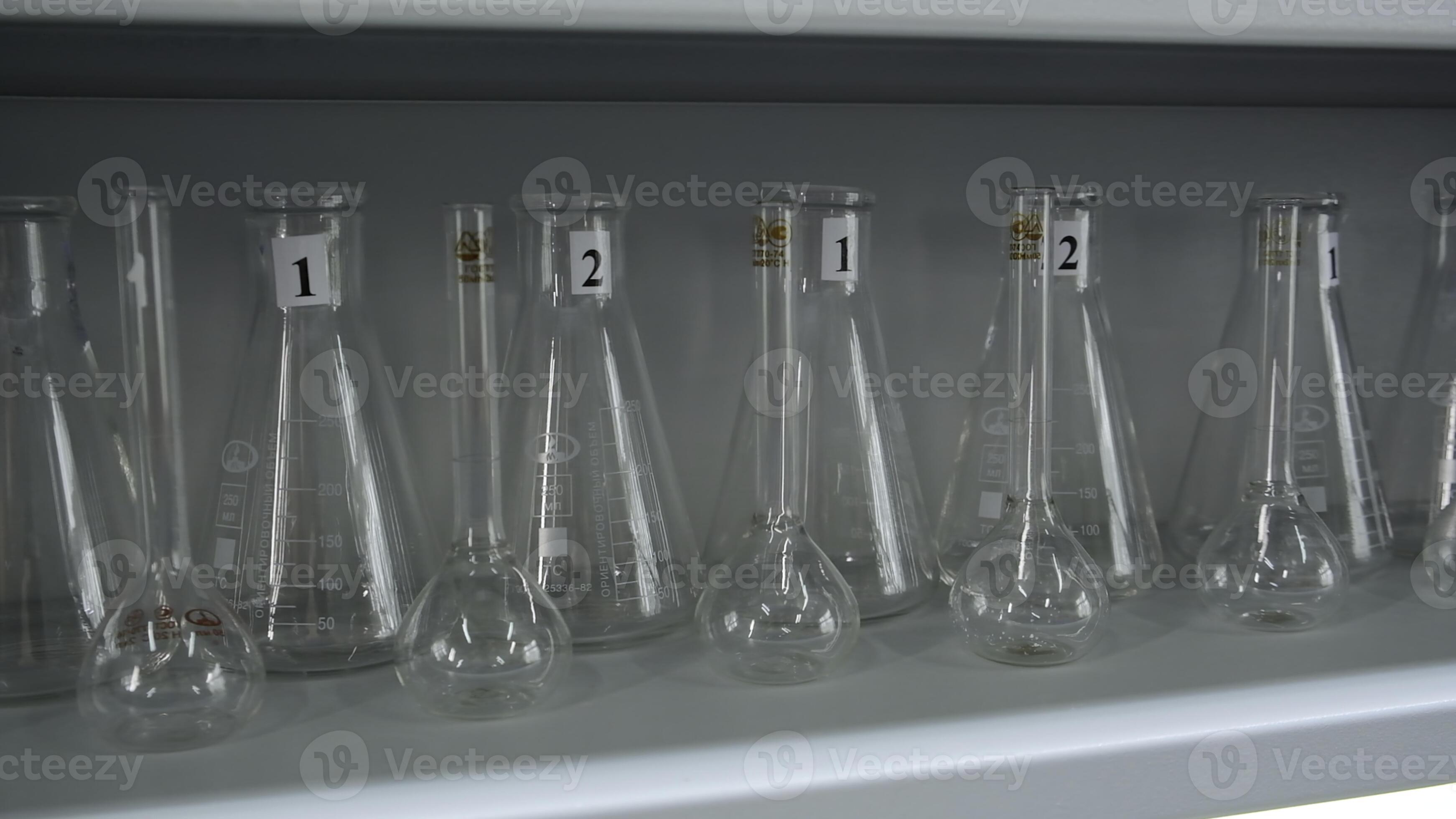 multiple laboratory flasks on the shelf ready to be used. Clip. Hand of ...