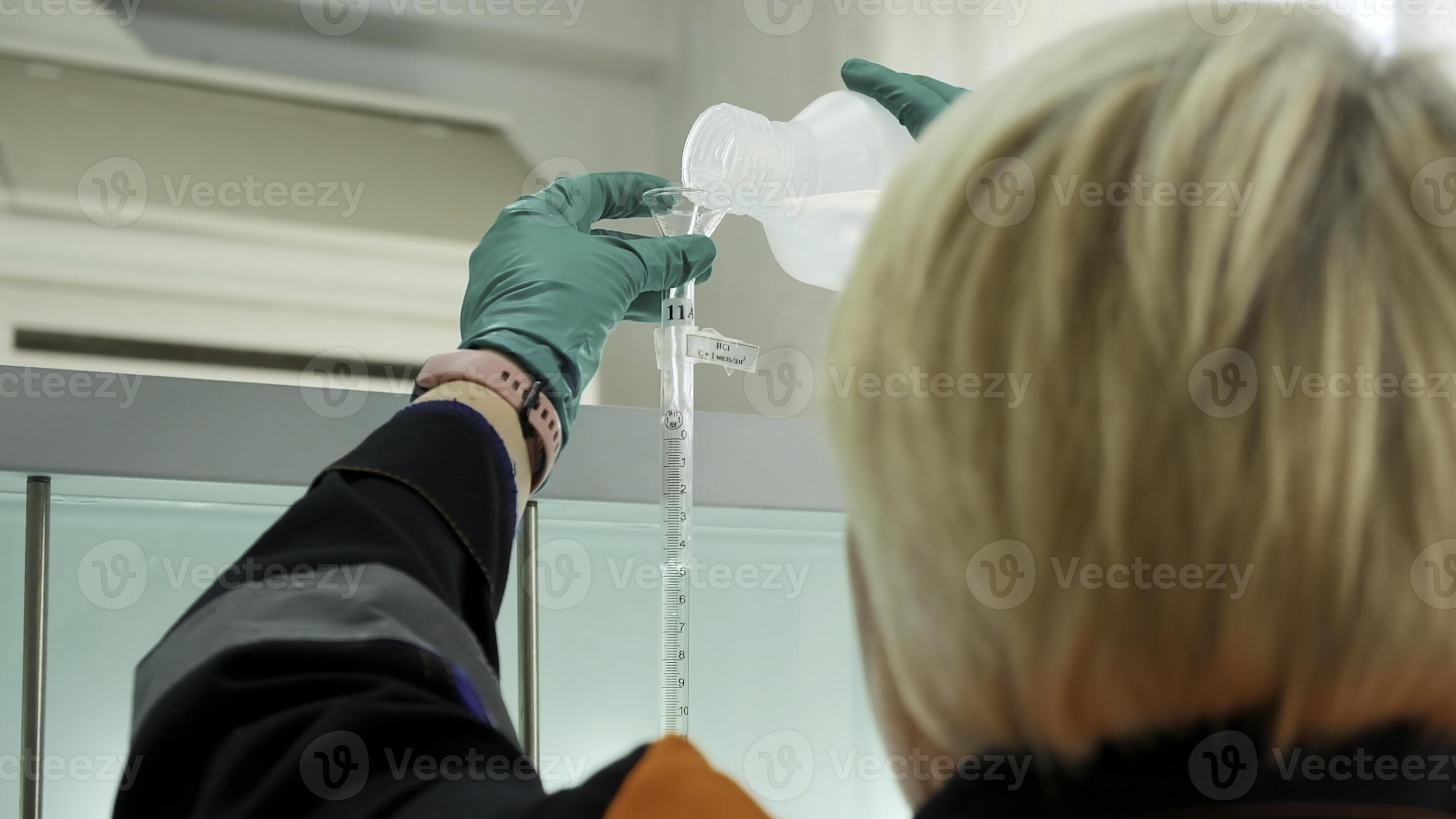 Chemists mixing up solutions at the lab. Clip. View over the shoulder of a woman in gloves ...