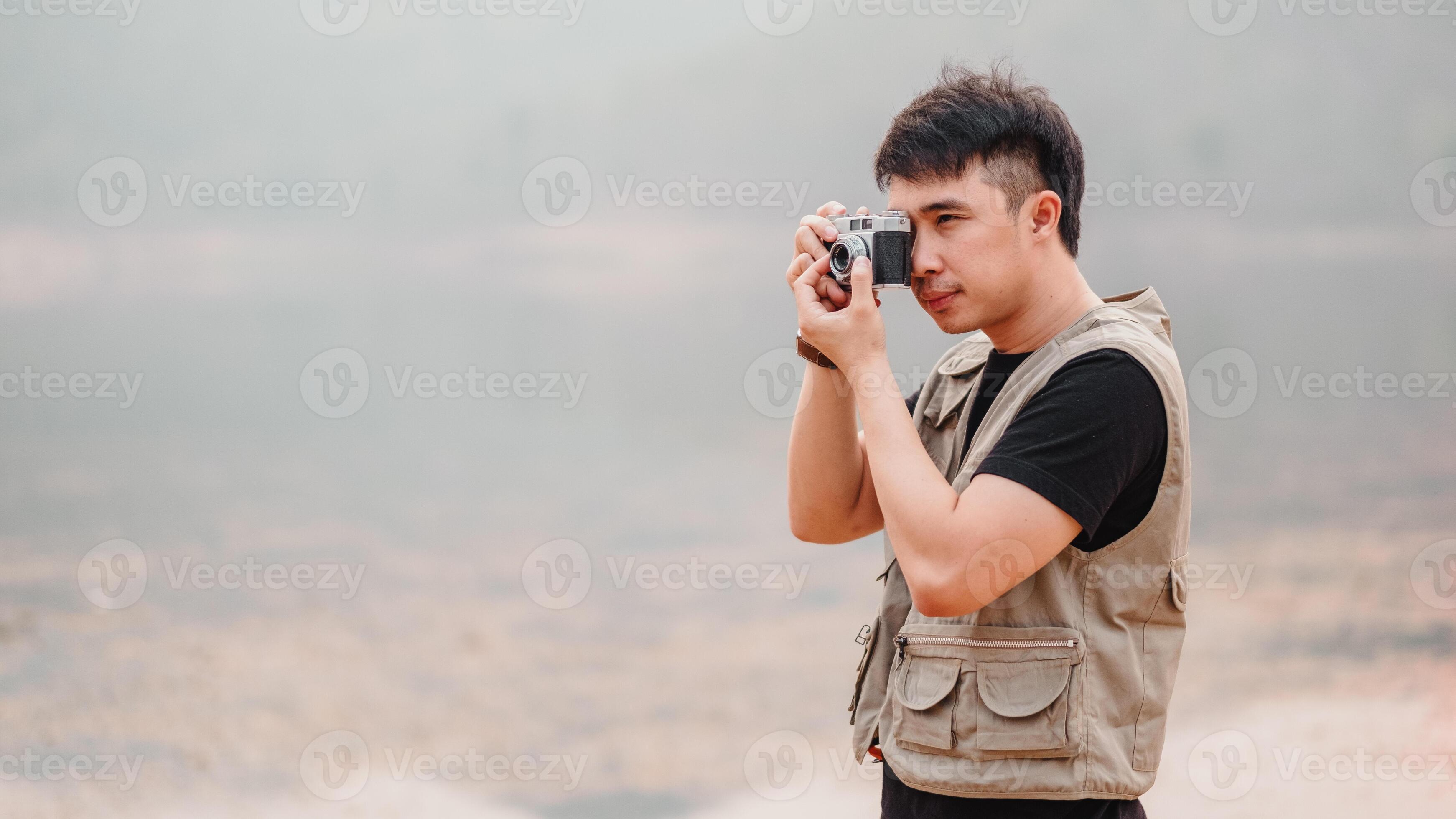Young man with a vintage camera captures the beauty of the outdoors on a hazy day. 42537495 ...