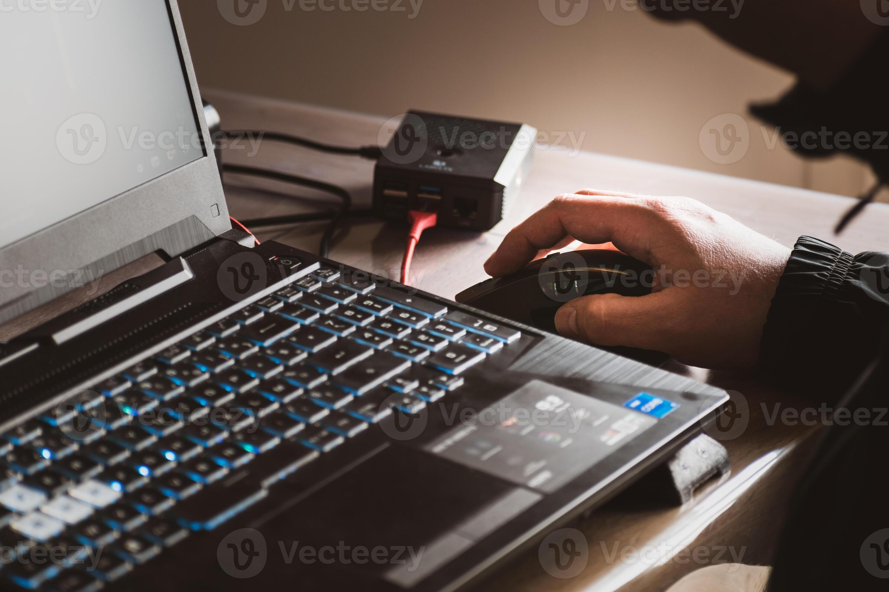 Close up of man's hand using wireless mouse, Raspberry Pi and laptop computer with blue backlit ...