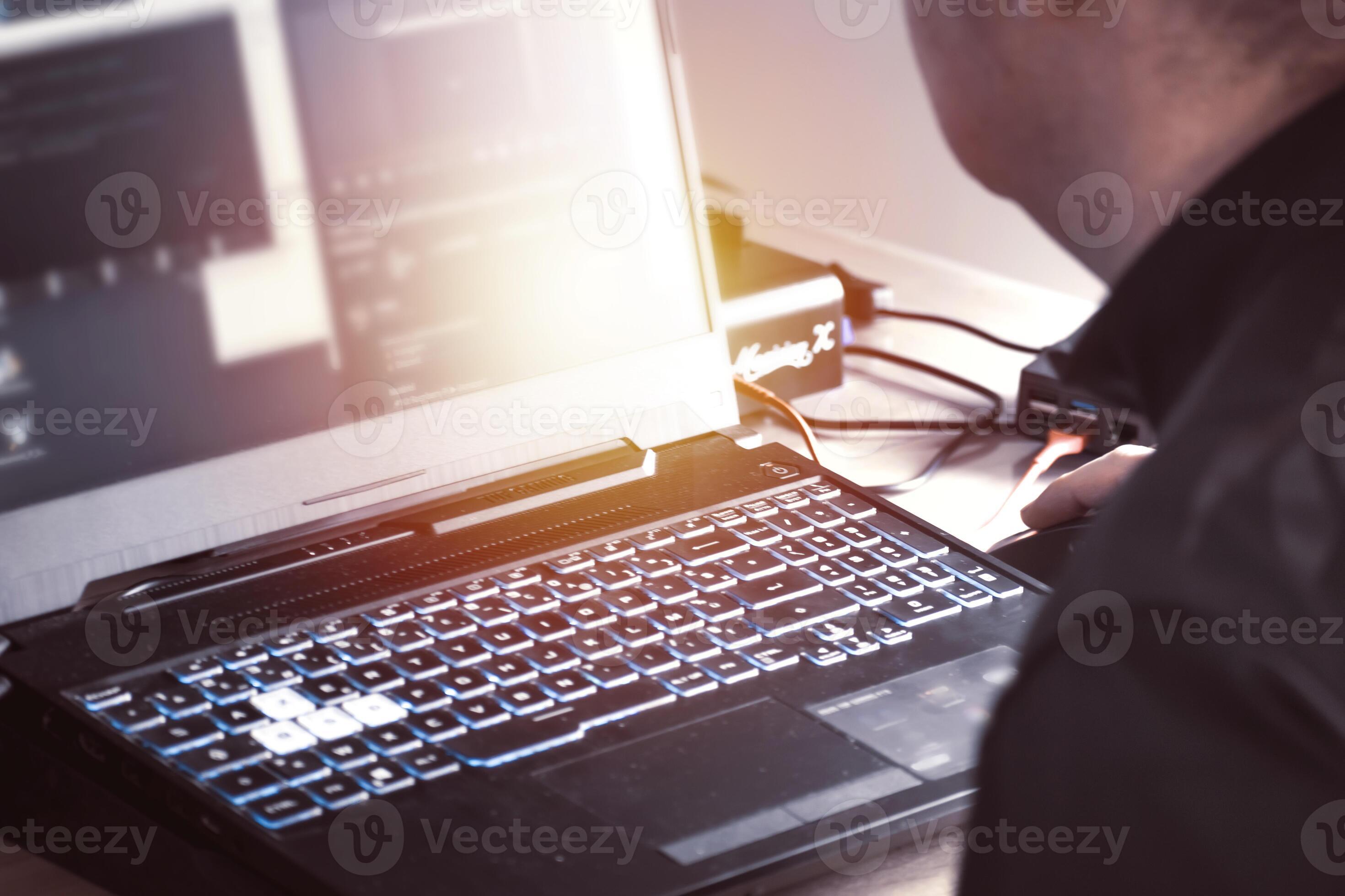 Close up of man's hand using wireless mouse and laptop computer with blue backlit keyboard ...