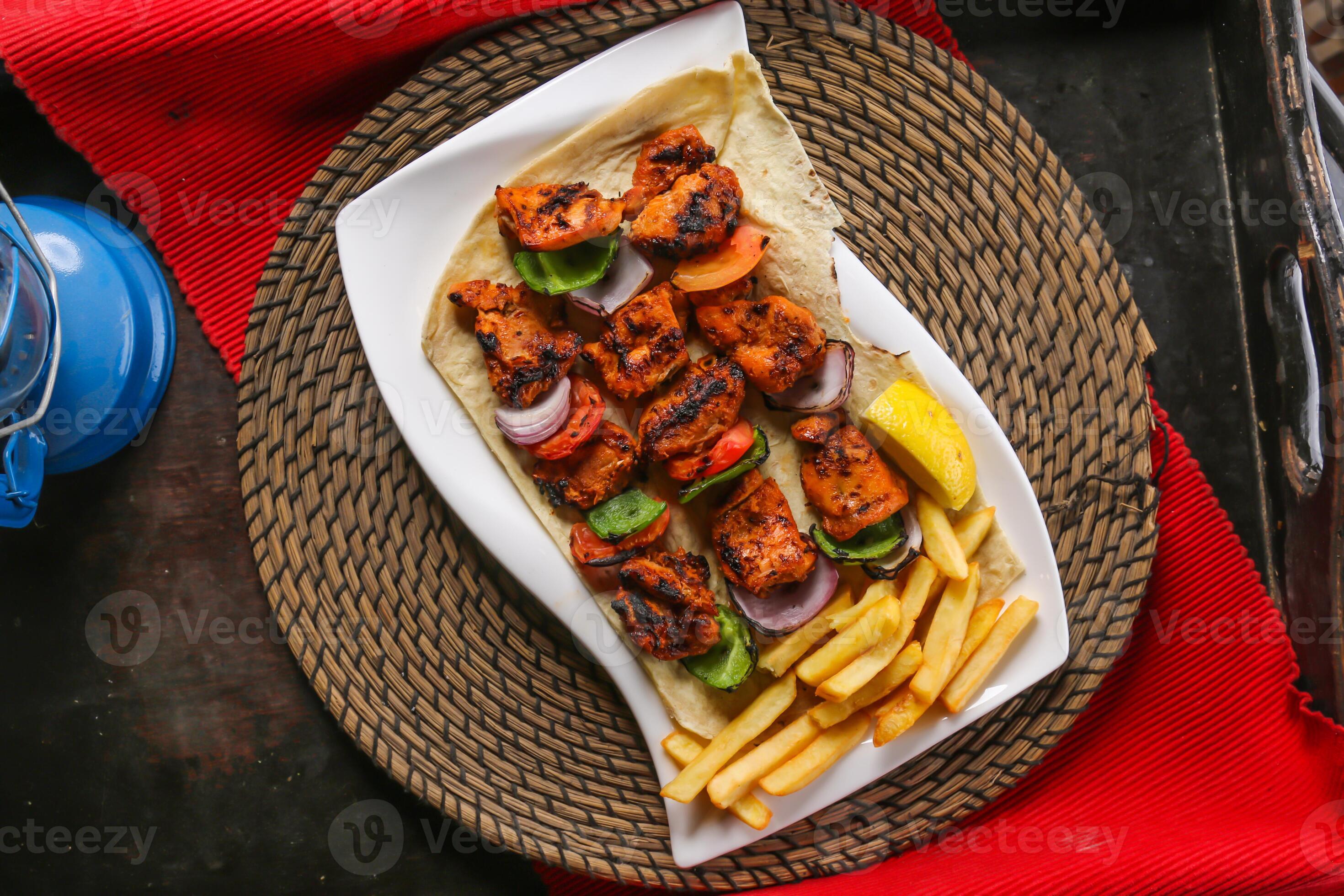 Shish Tawook or tikka kabab with fries, lemon and bread served in dish ...