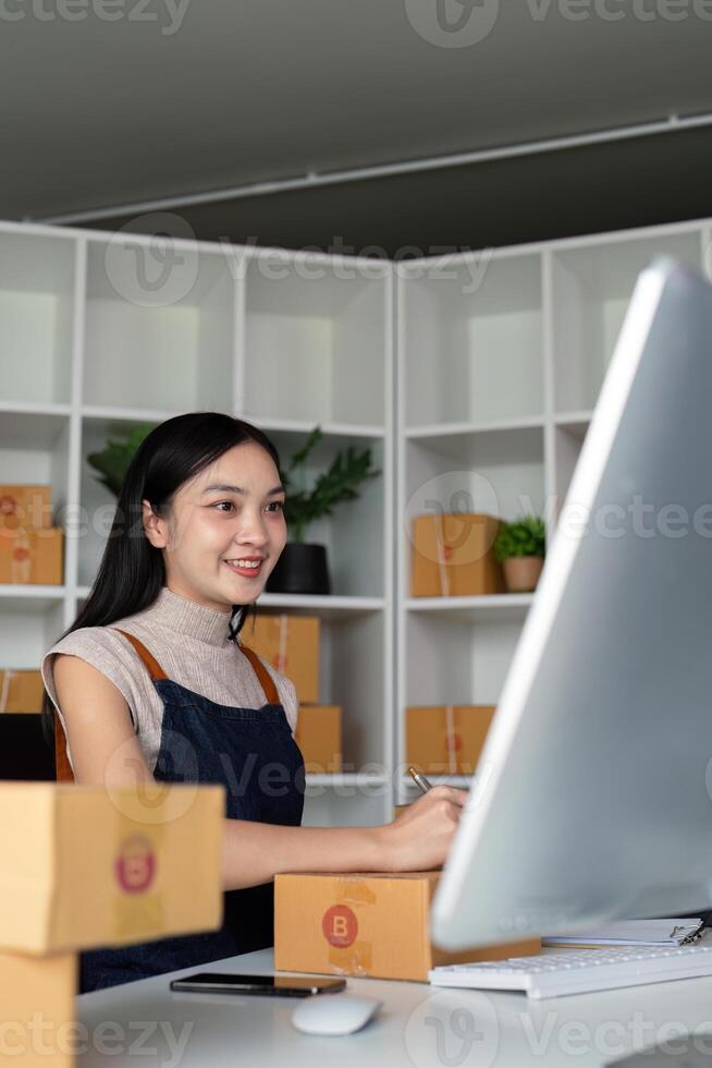 Woman asian in an online store check the customer address and package information on the laptop ...