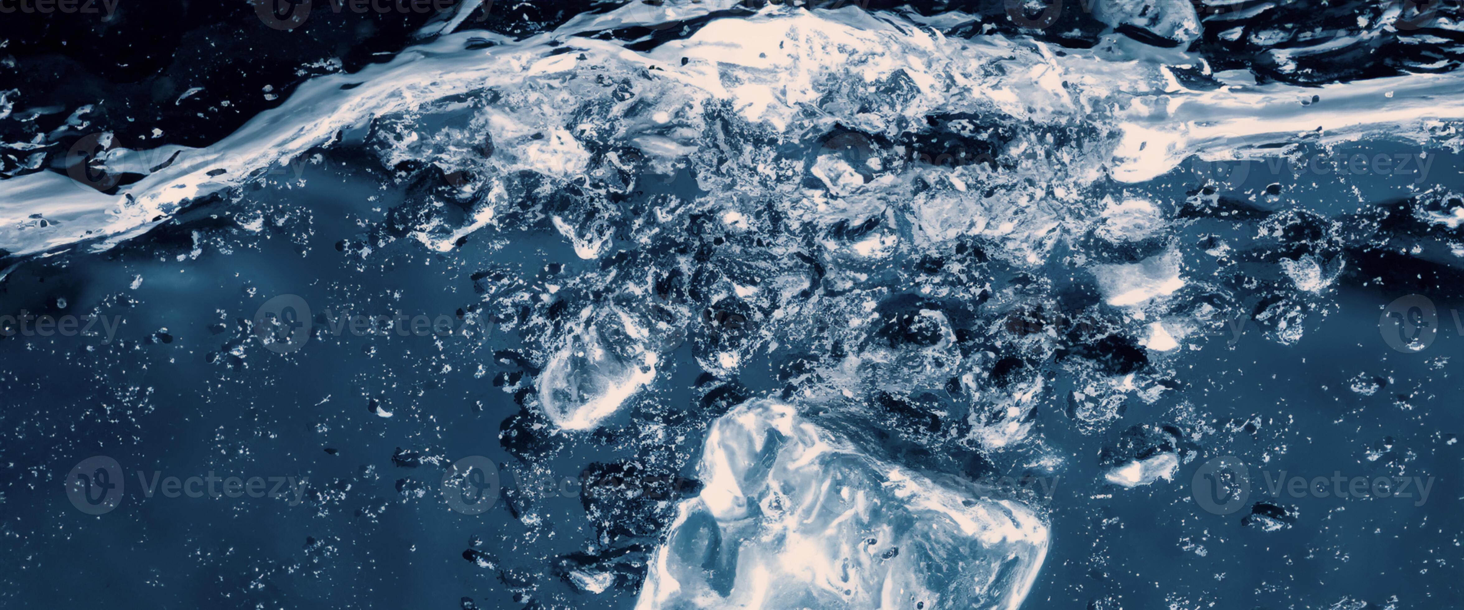 Water splashing and ice cube. Ice splashing into a glass of water. Underwater pouring ice cubes ...