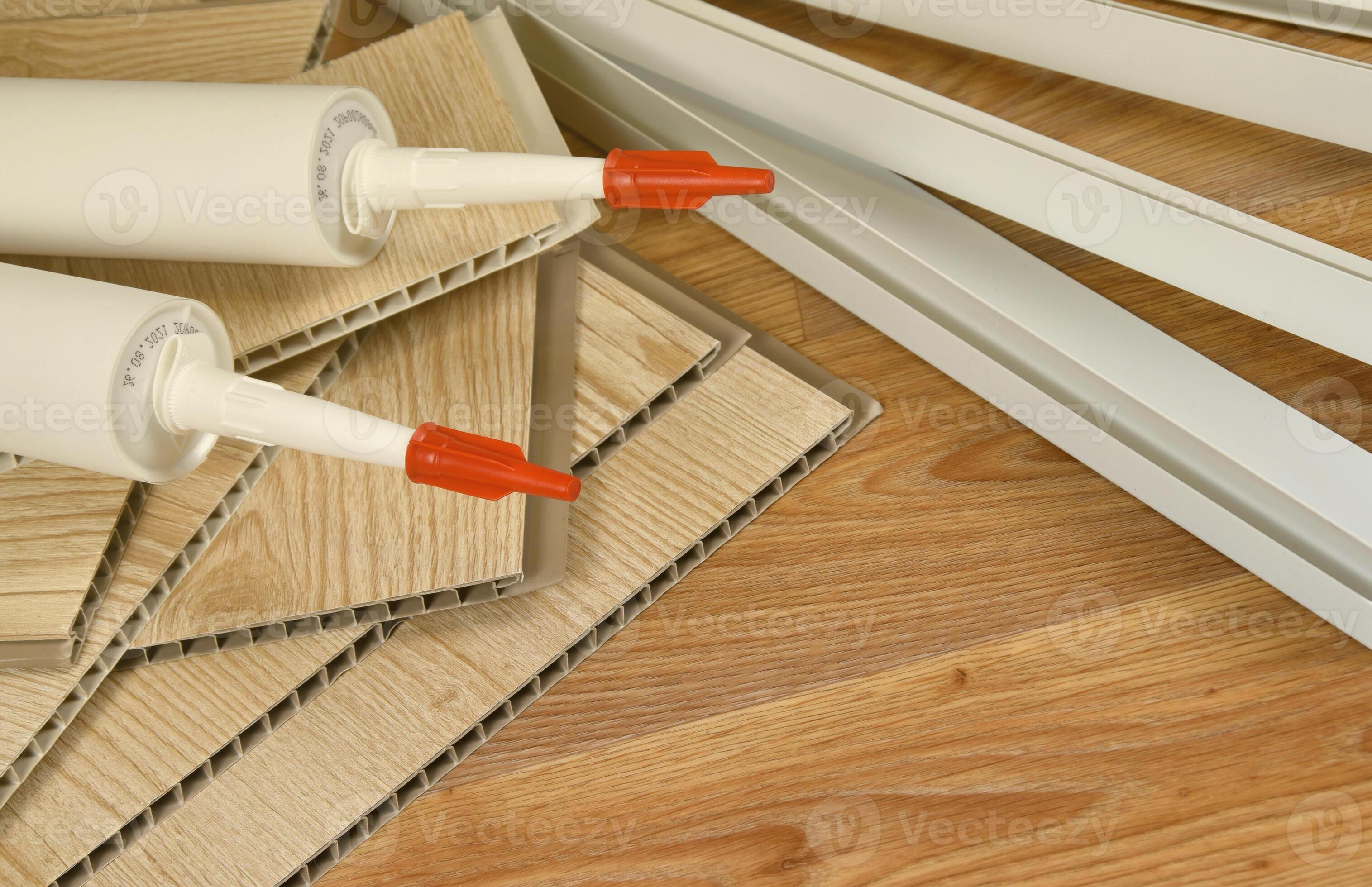 Set of items for PVC ceiling indoor works. Assembly adhesive bottles and PVC panels with plastic ...