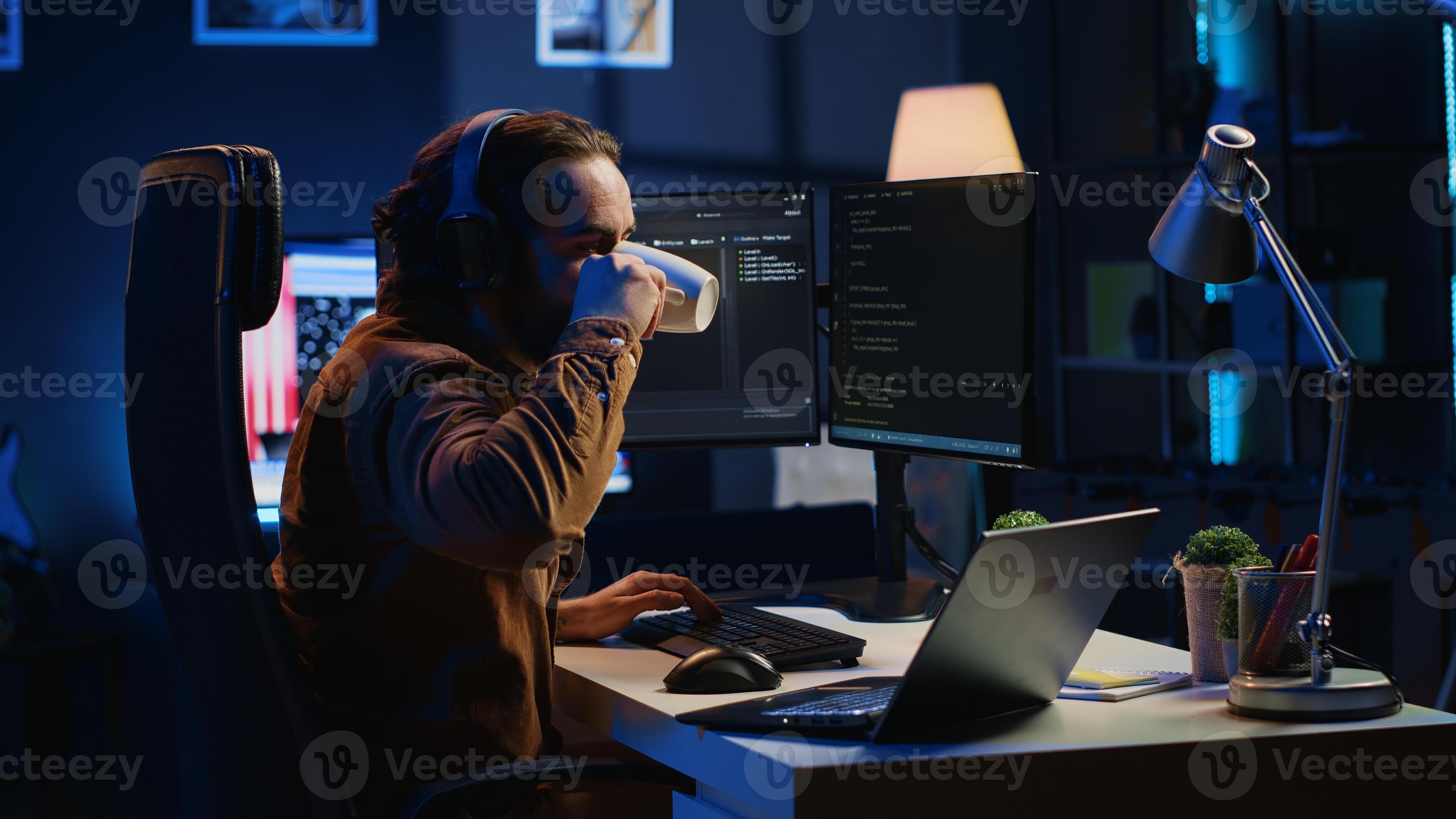 Programmer does multitasking to finish developing PC code, drinks coffee, listens music. IT ...