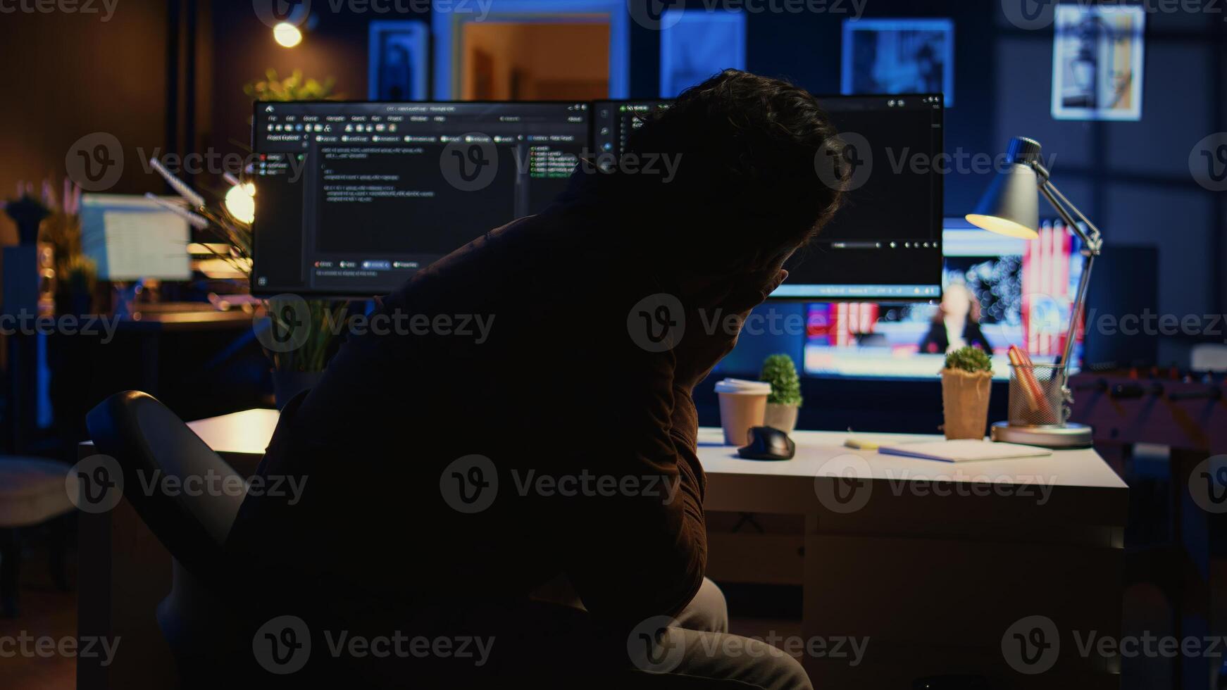 Software developer putting face in hands in frustration while updating binary code script on ...