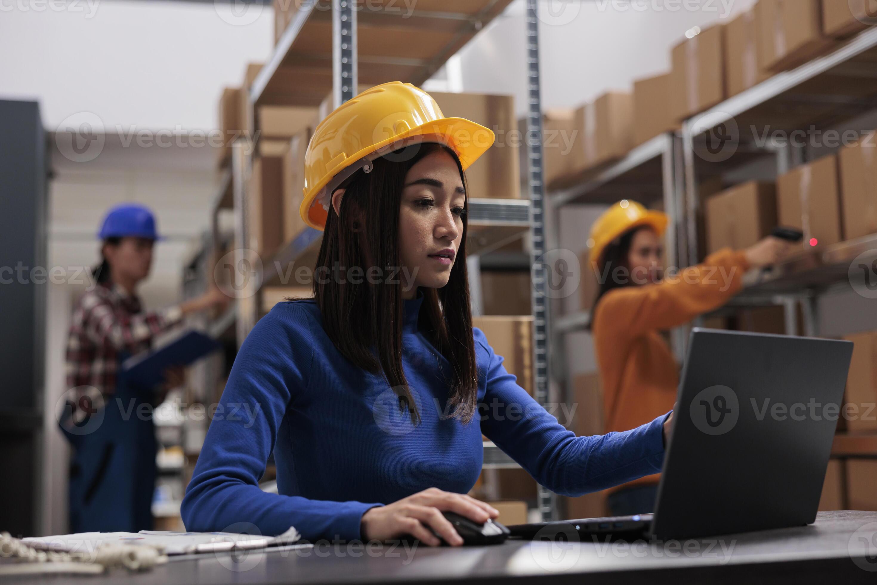 Asian retail storehouse employee analyzing orders checklist on laptop while working in storage ...