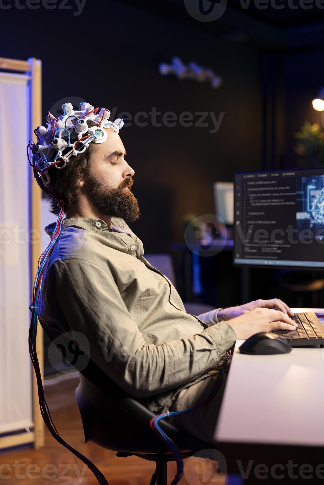 Man with EEG headset on typing on keyboard, writing code allowing him ...