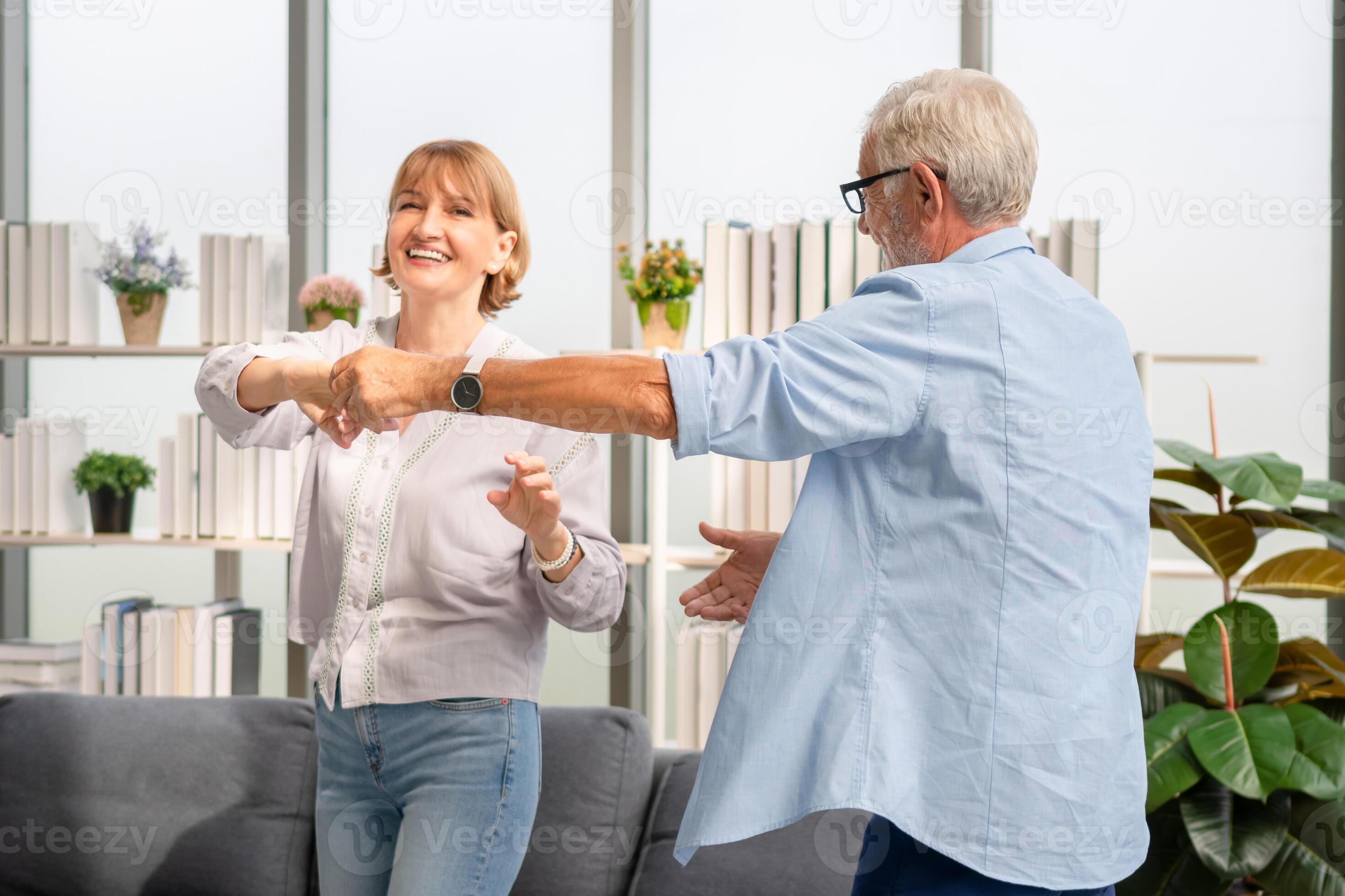 Happy senior couple dancing in living room, Senior couple spending time together in the living ...