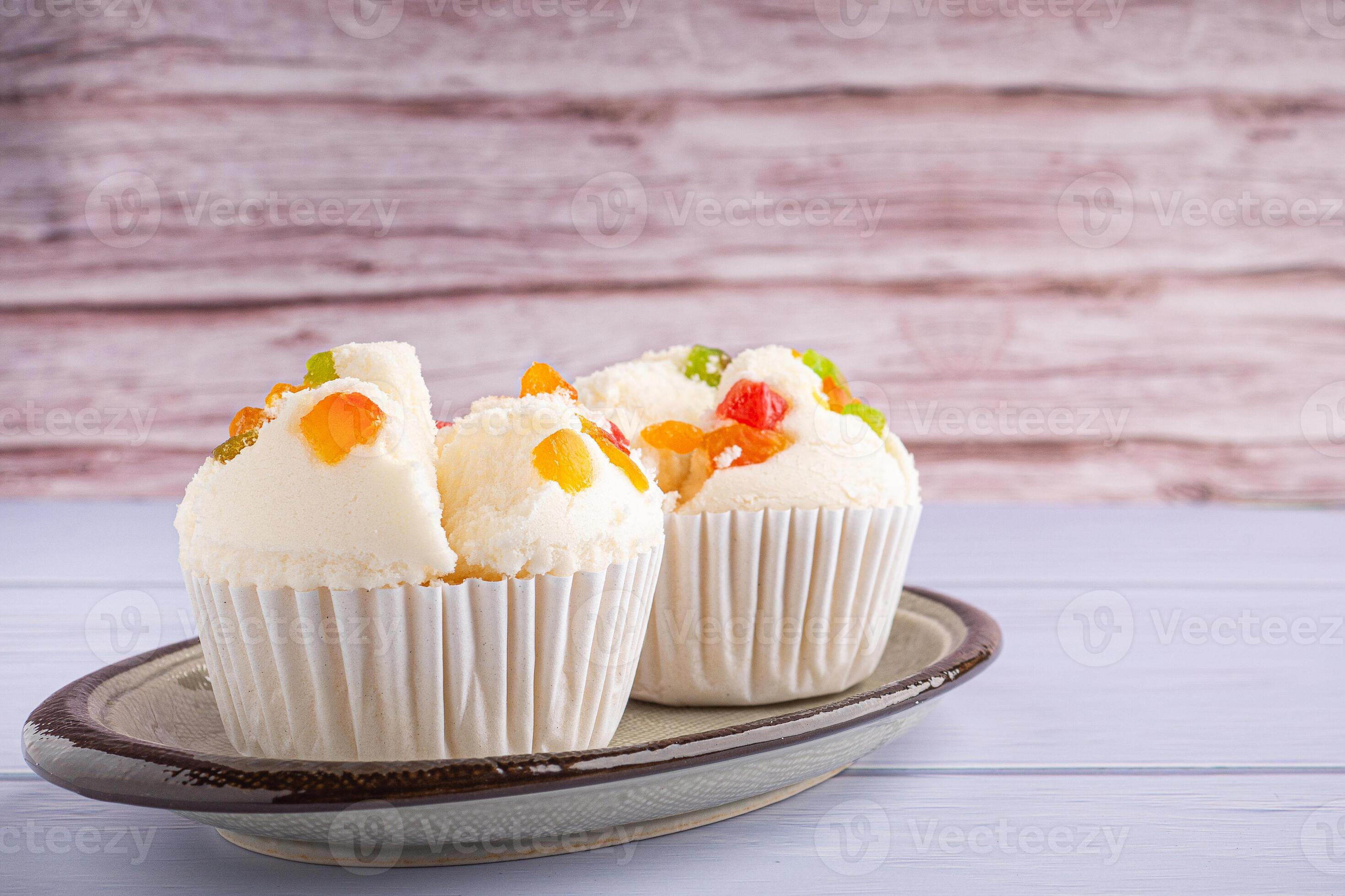 Side view of Thai steamed cupcakes topped with dry fruit on plate on blue cloth with wooden ...