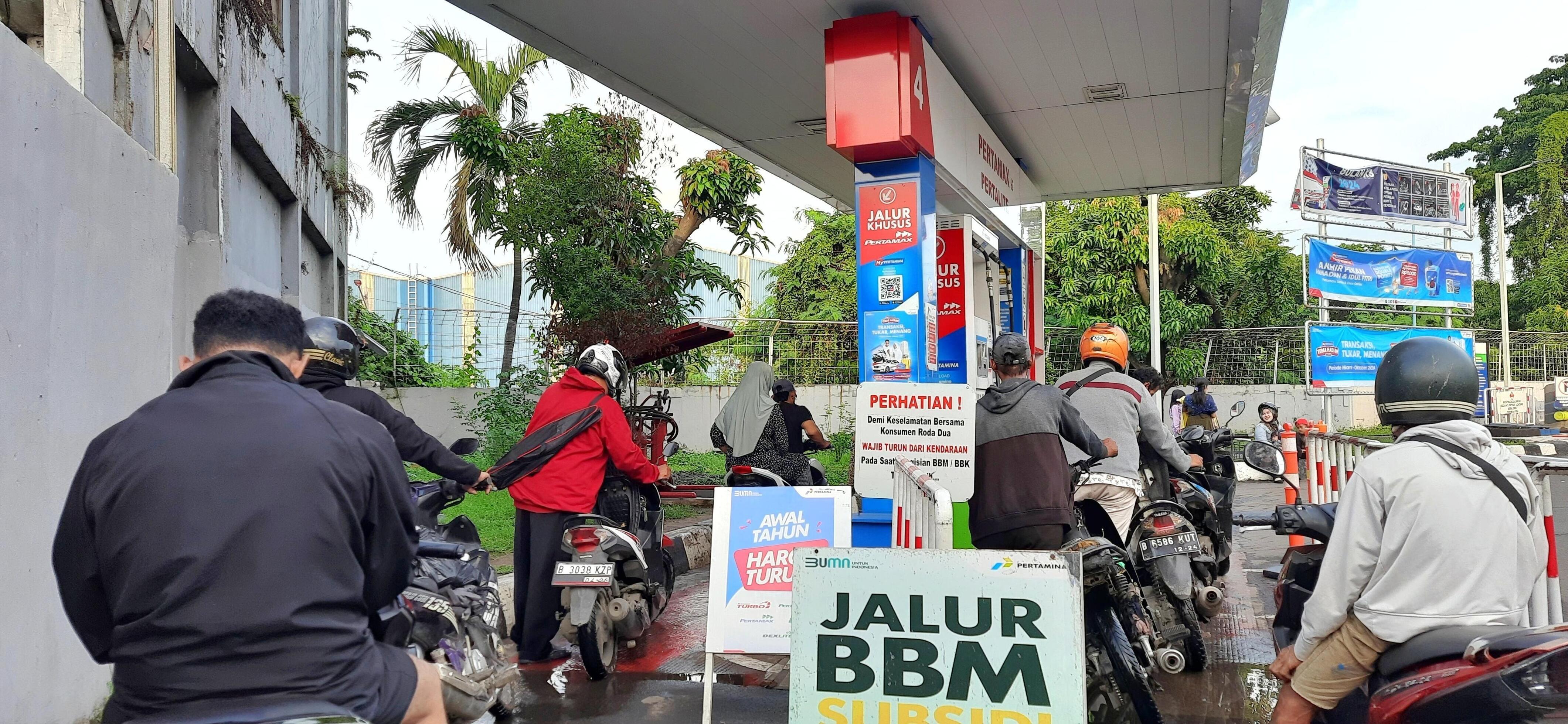 Long queue of motorbike drivers public refueling at Pertamina gas station. Bekasi, West Java ...