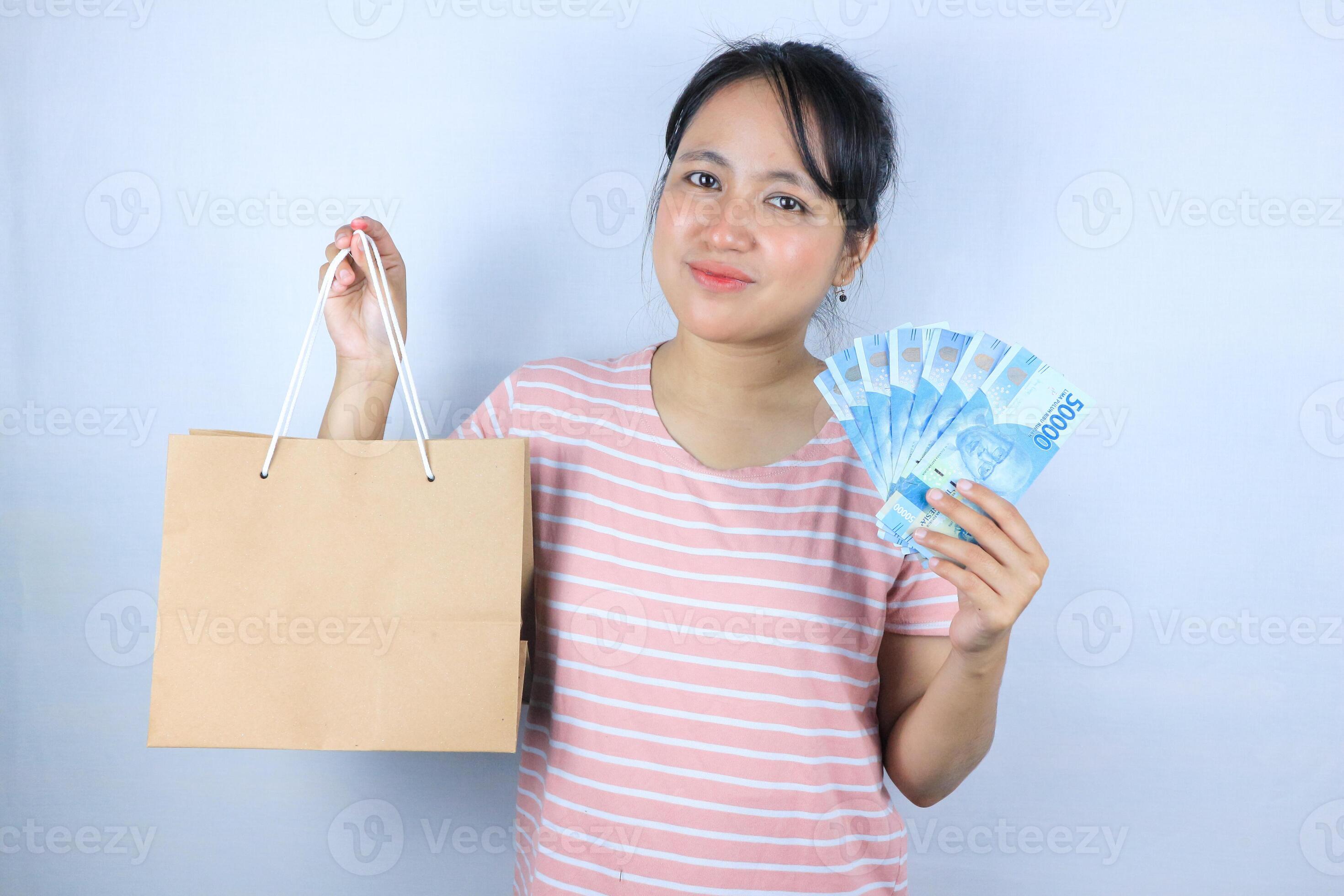 Young Beautiful Asian Woman Holding Paper Shopping Bag And Showing Cash
