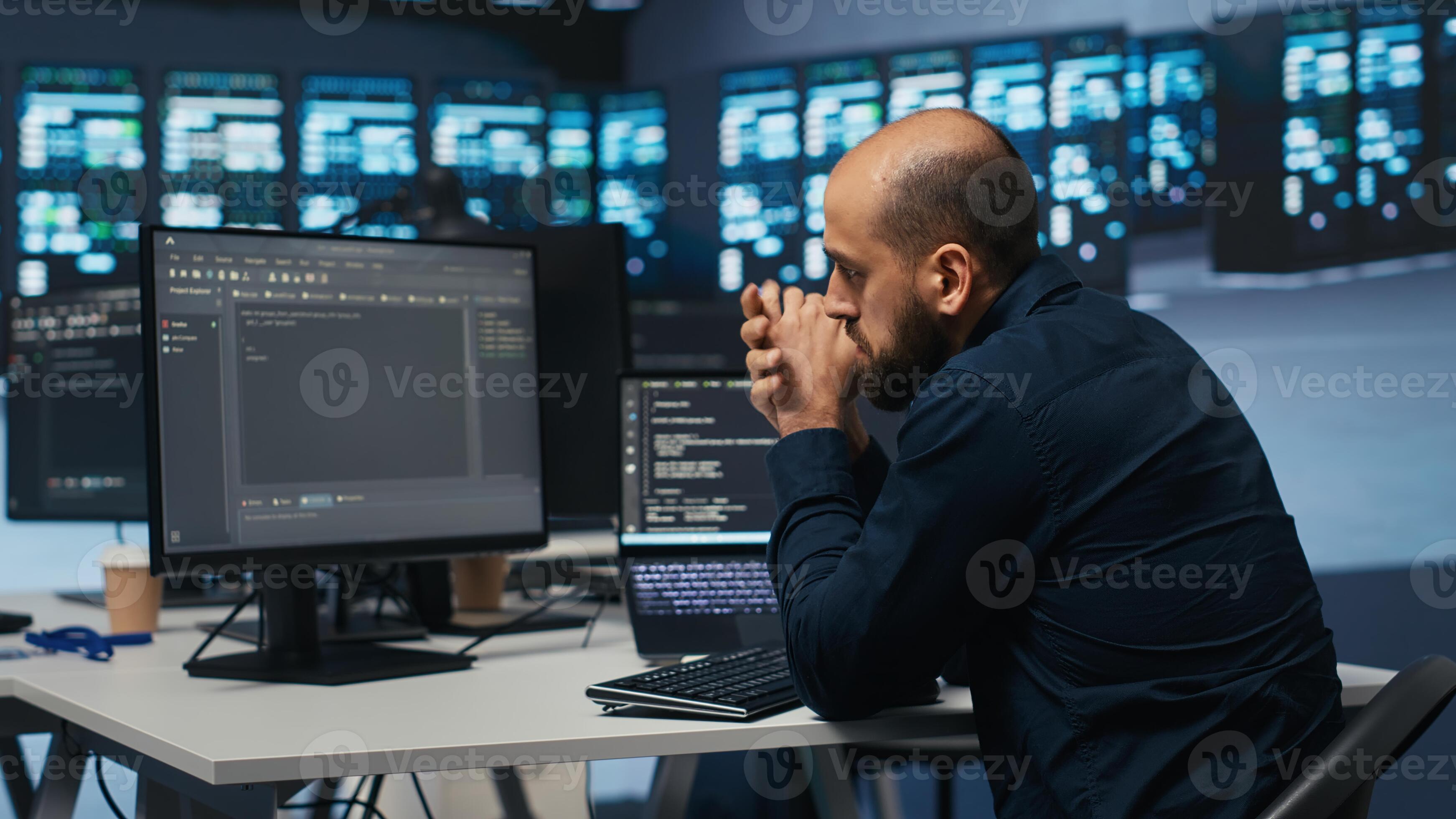 Man In Server Room Typing Code On Laptop And Pc Ensuring Data Remains