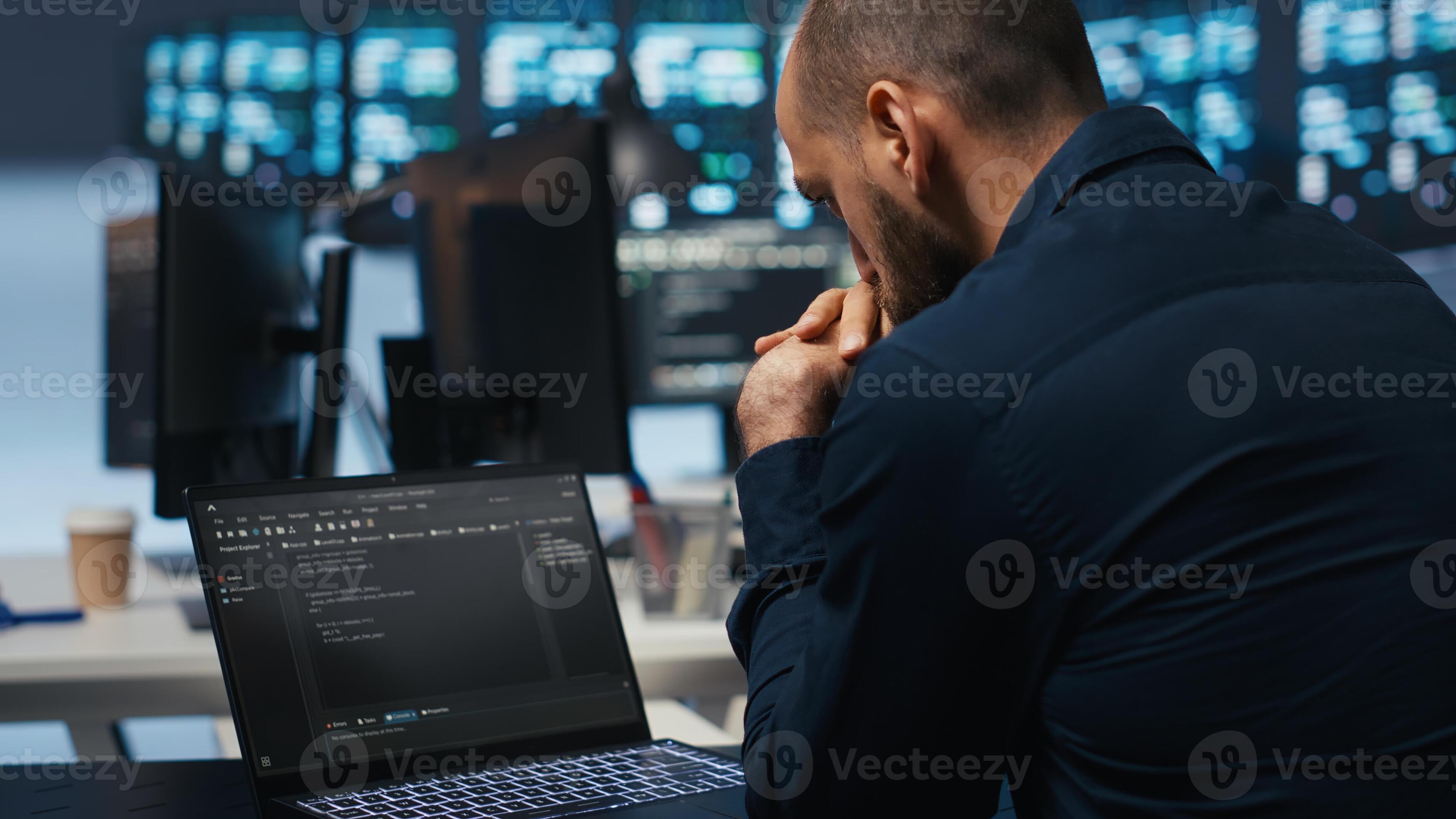 Computer scientist overseeing data center servers, typing code on laptop, troubleshooting rigs ...