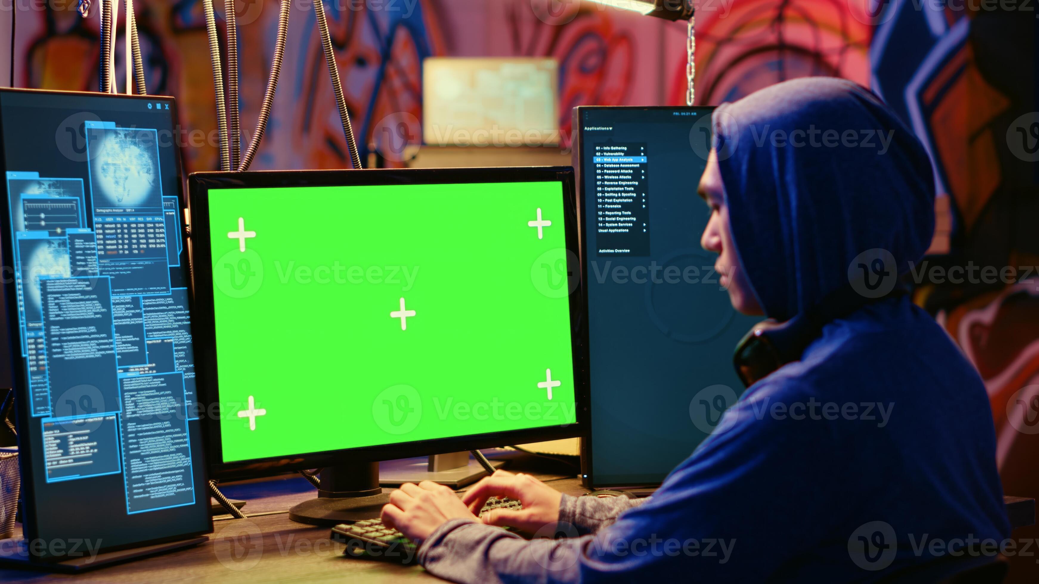Asian hacker in hidden place with graffiti walls using green screen computer to deploy malware ...