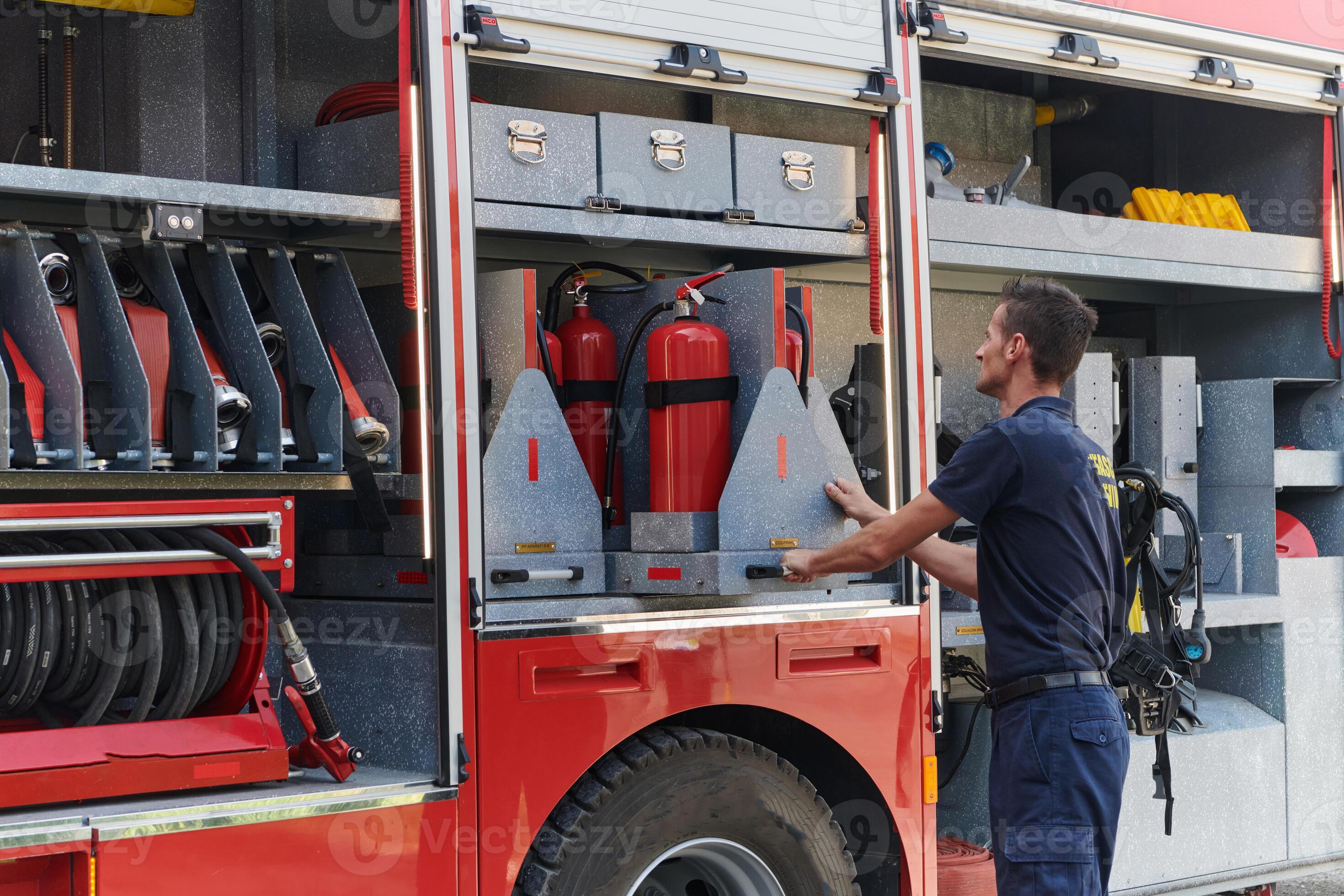 A dedicated firefighter preparing a modern firetruck for deployment to ...