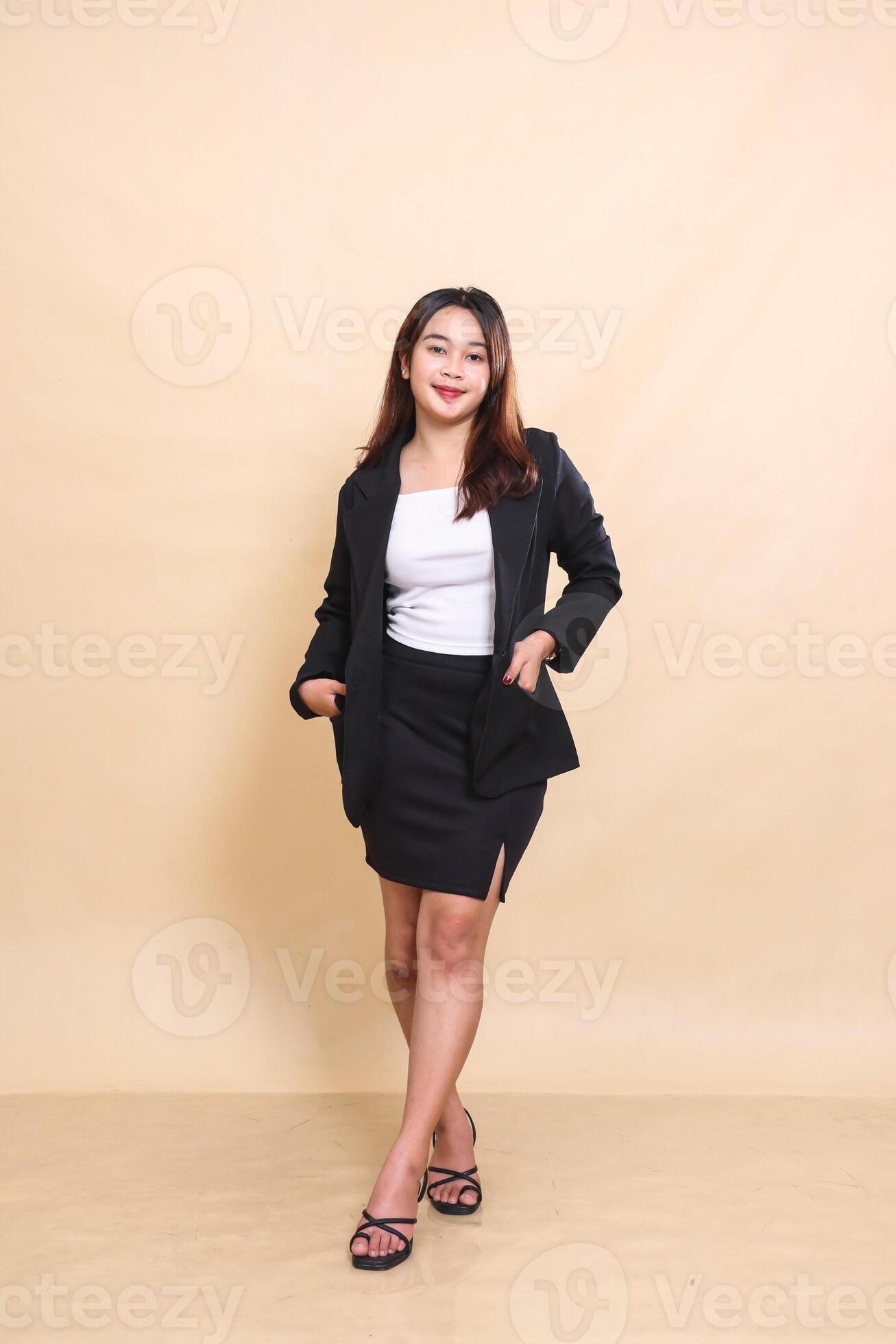 Beautiful young Asian executive woman standing smiling and looking at ... Beautiful young Asian executive woman standing smiling and looking at ...