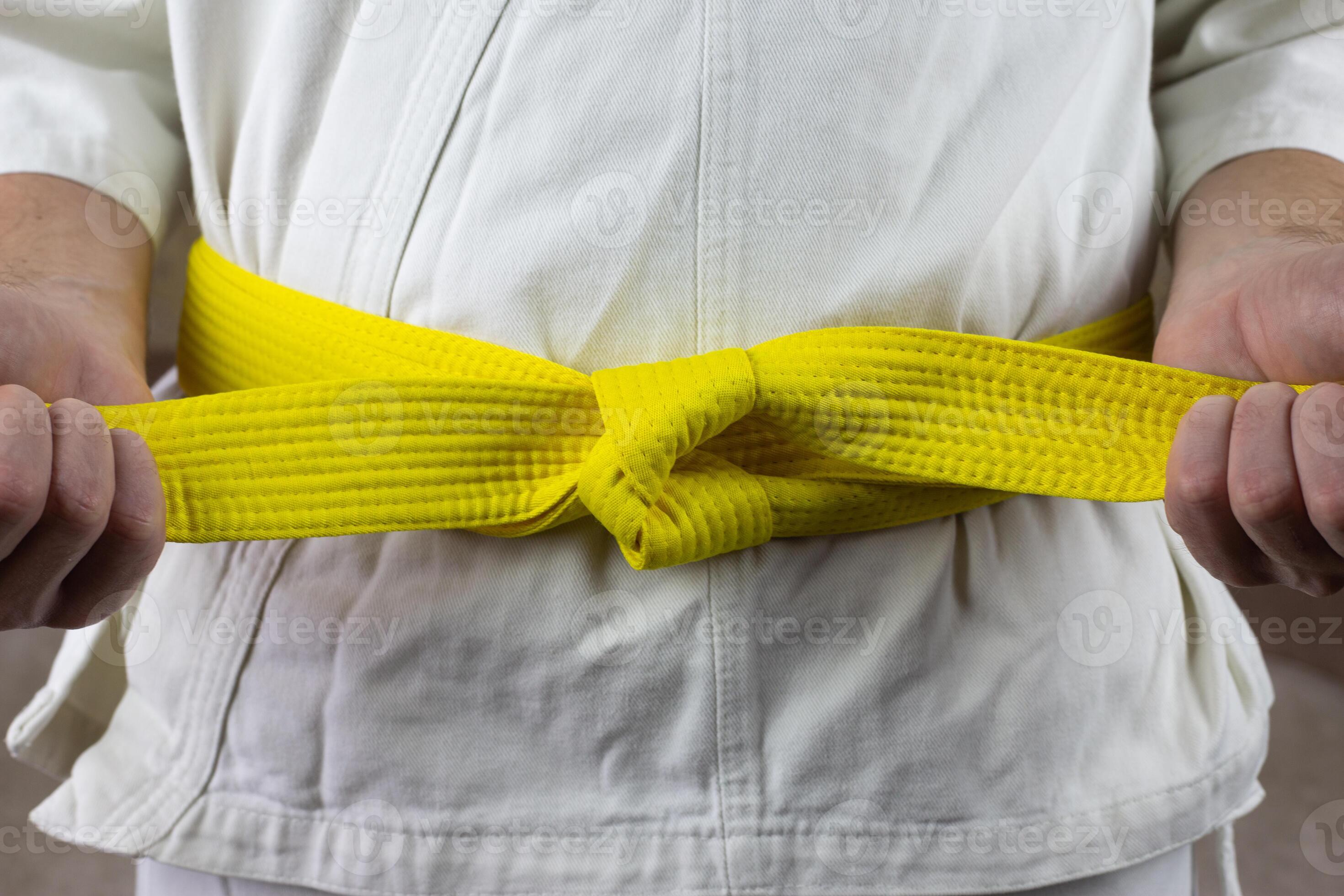 Male hands tighten yellow belt in Kyokushin karate, Asian types of ...