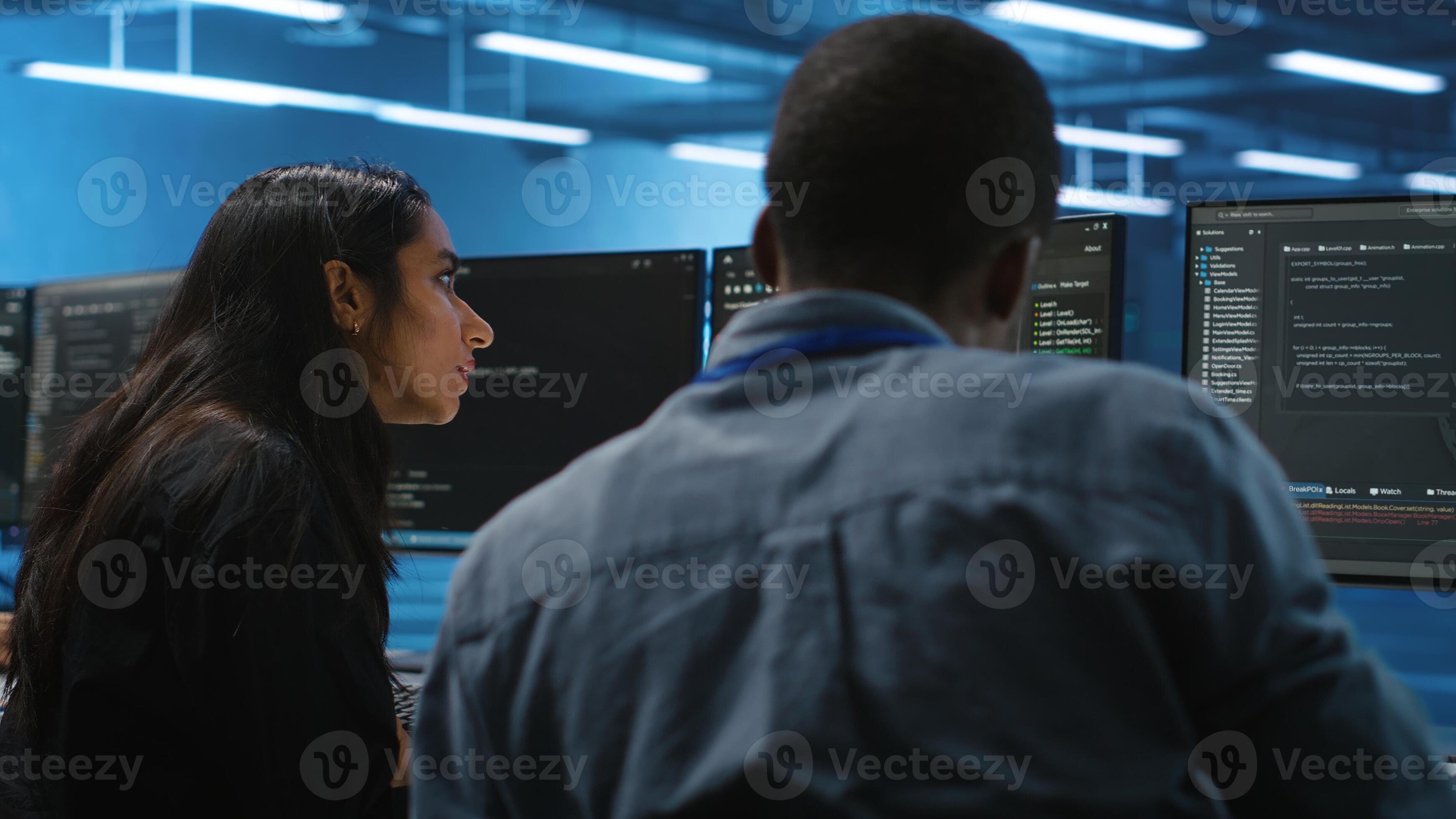 Diverse IT engineers in server room brainstorming ways to fix equipment storing datasets ...