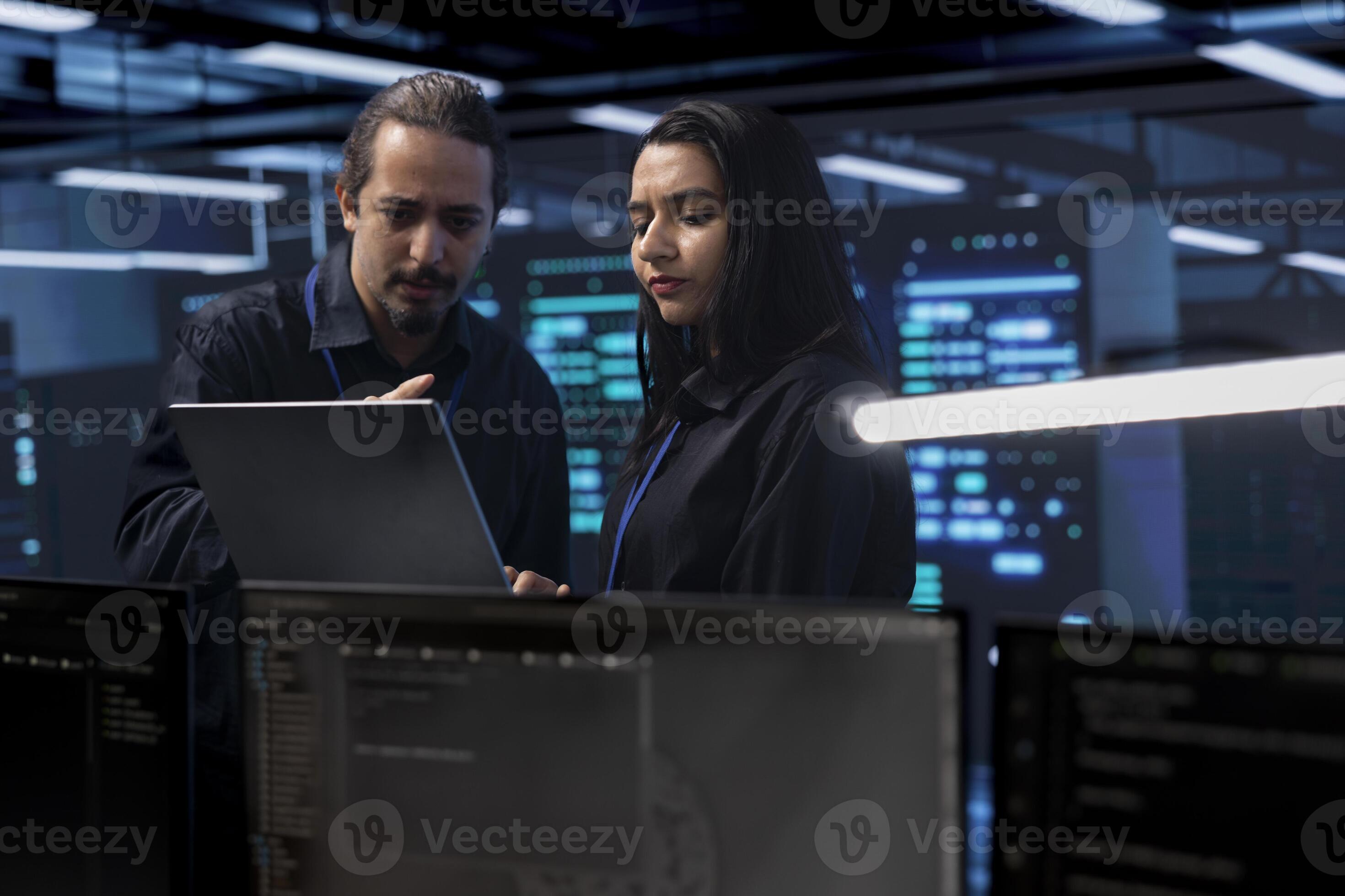 Programmers in server room checking recovery plan, monitoring tech gear energy consumption using ...