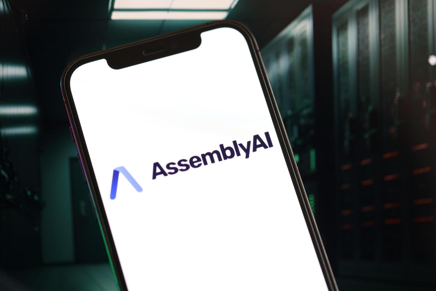 KYIV, UKRAINE - MARCH 17, 2024 AssemblyAI logo on iPhone display screen with background of ...