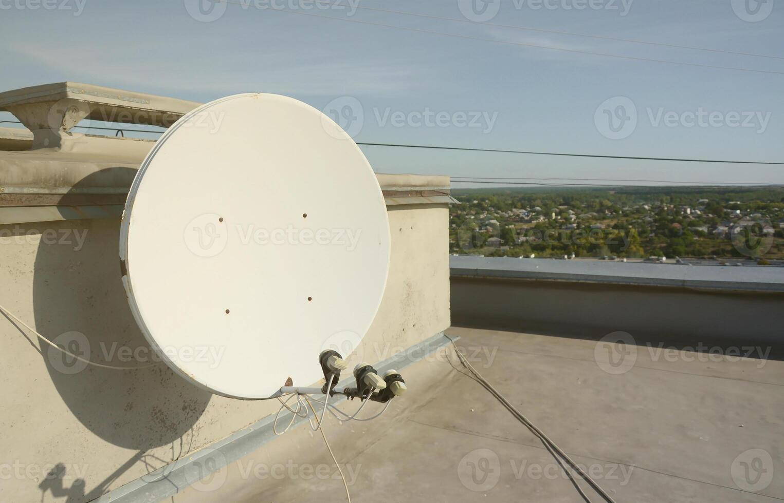 White satellite dish with three converters mounted on residental ...
