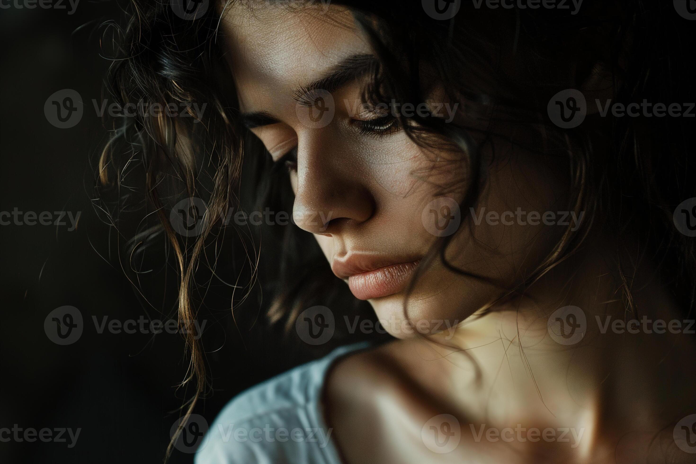 Intensely emotional portrait of a woman in despair, her face partly obscured by shadows ...