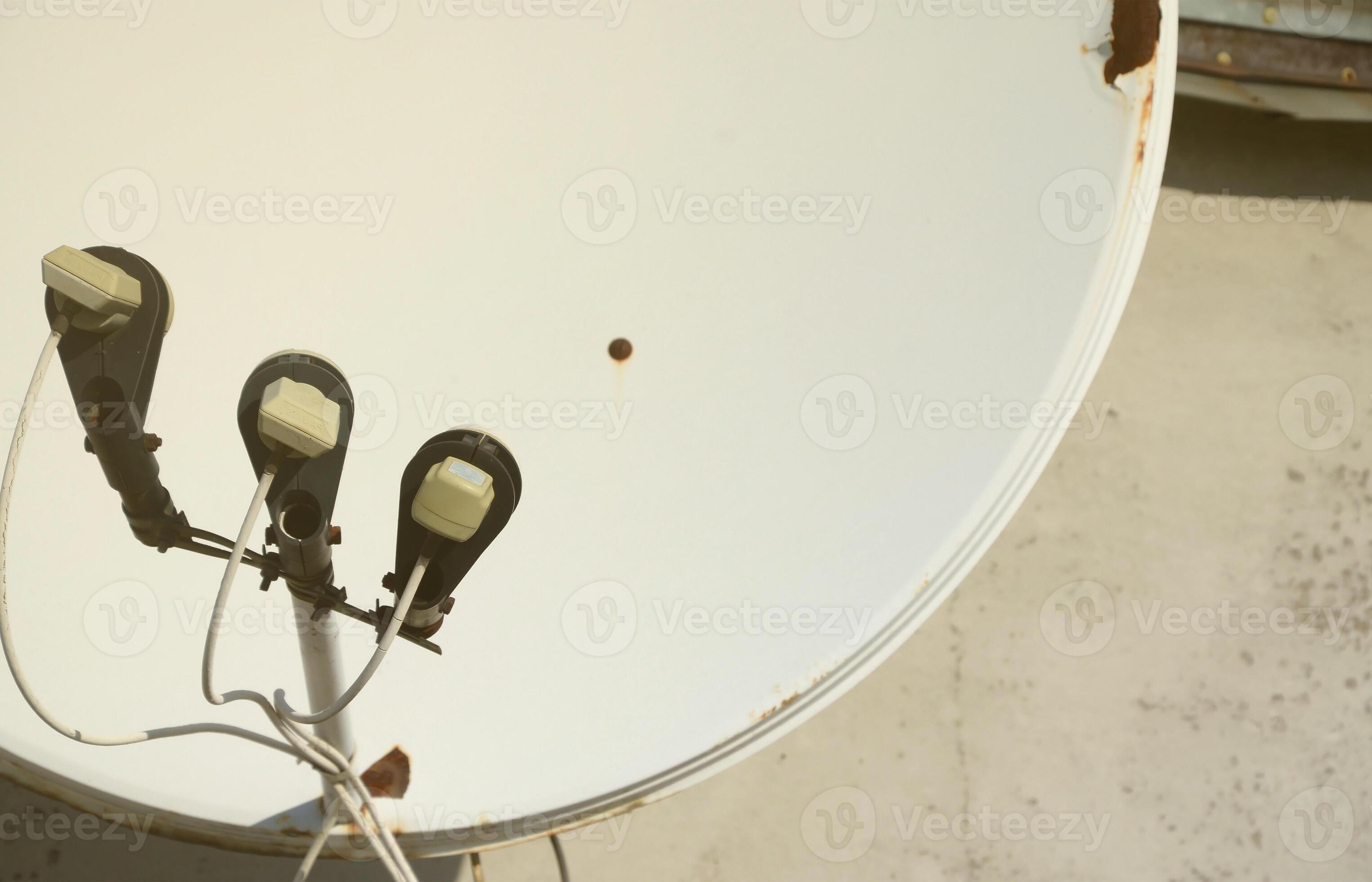 White satellite dish with three converters mounted on residental ...