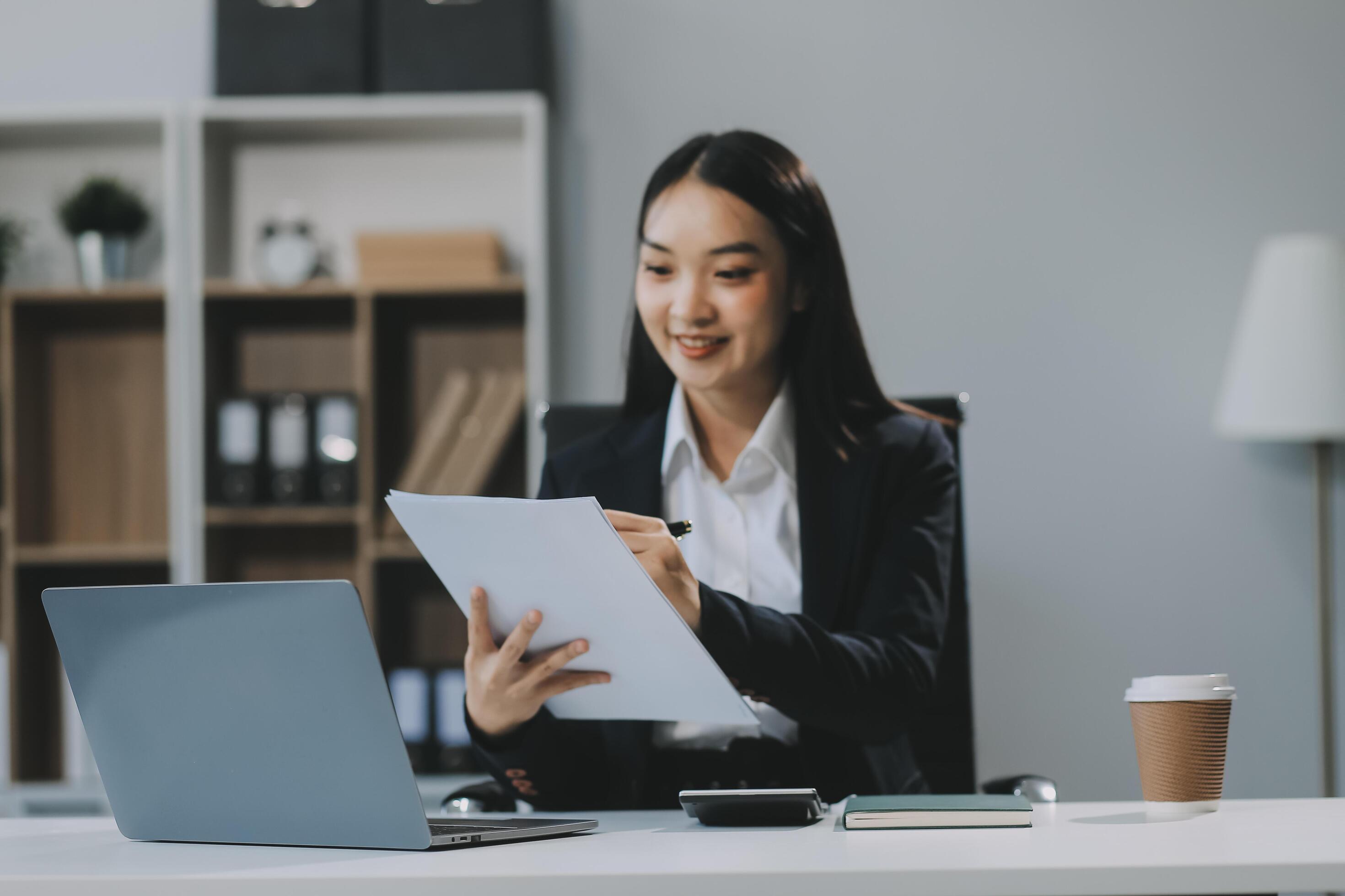 feliz joven empresaria asiática trabajando en una laptop y tomando notas en la oficina. 46672367 ...