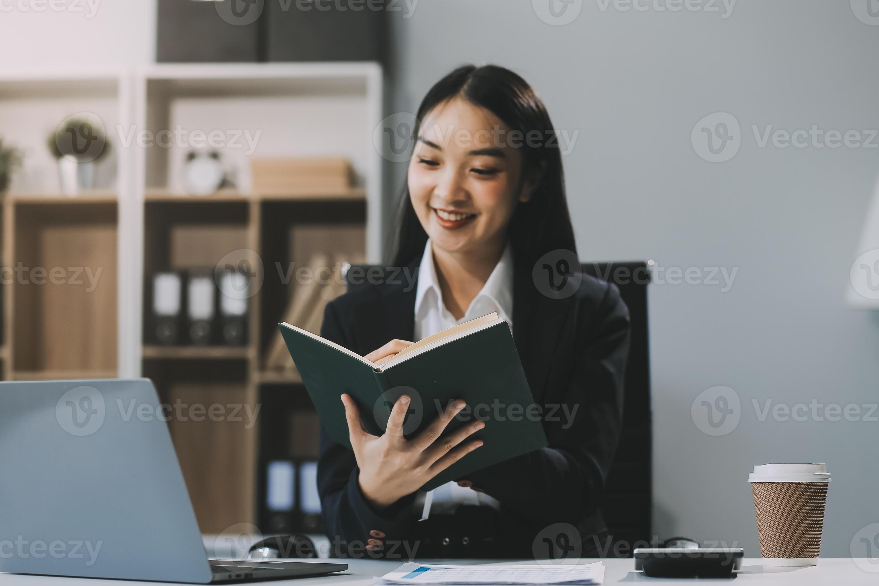 feliz joven empresaria asiática trabajando en una laptop y tomando notas en la oficina. 46672773 ...