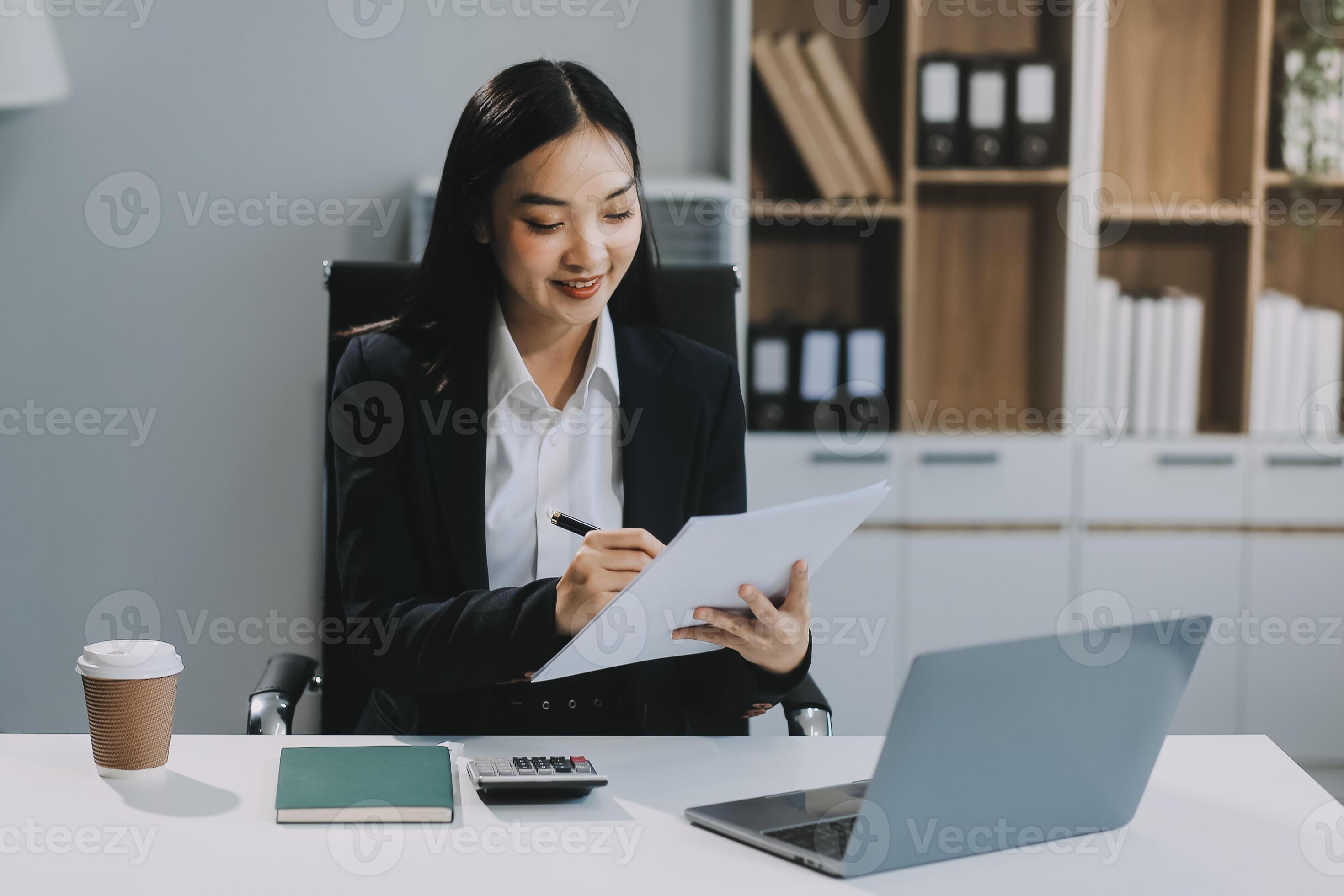 feliz joven empresaria asiática trabajando en una laptop y tomando notas en la oficina. 46672853 ...