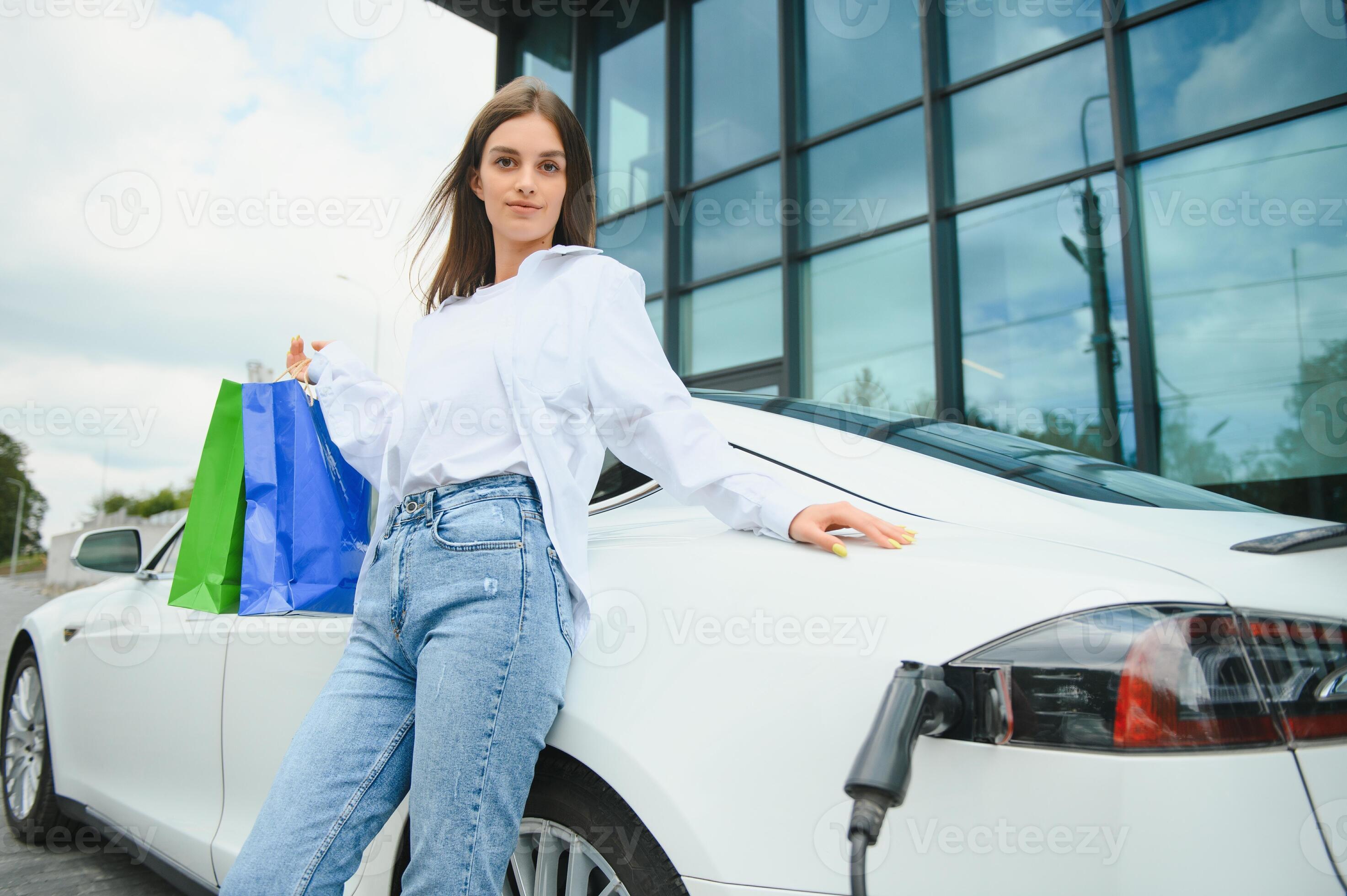 Electric car charging in street. Ecological Car Connected and Charging Batteries. Girl Waiting ...
