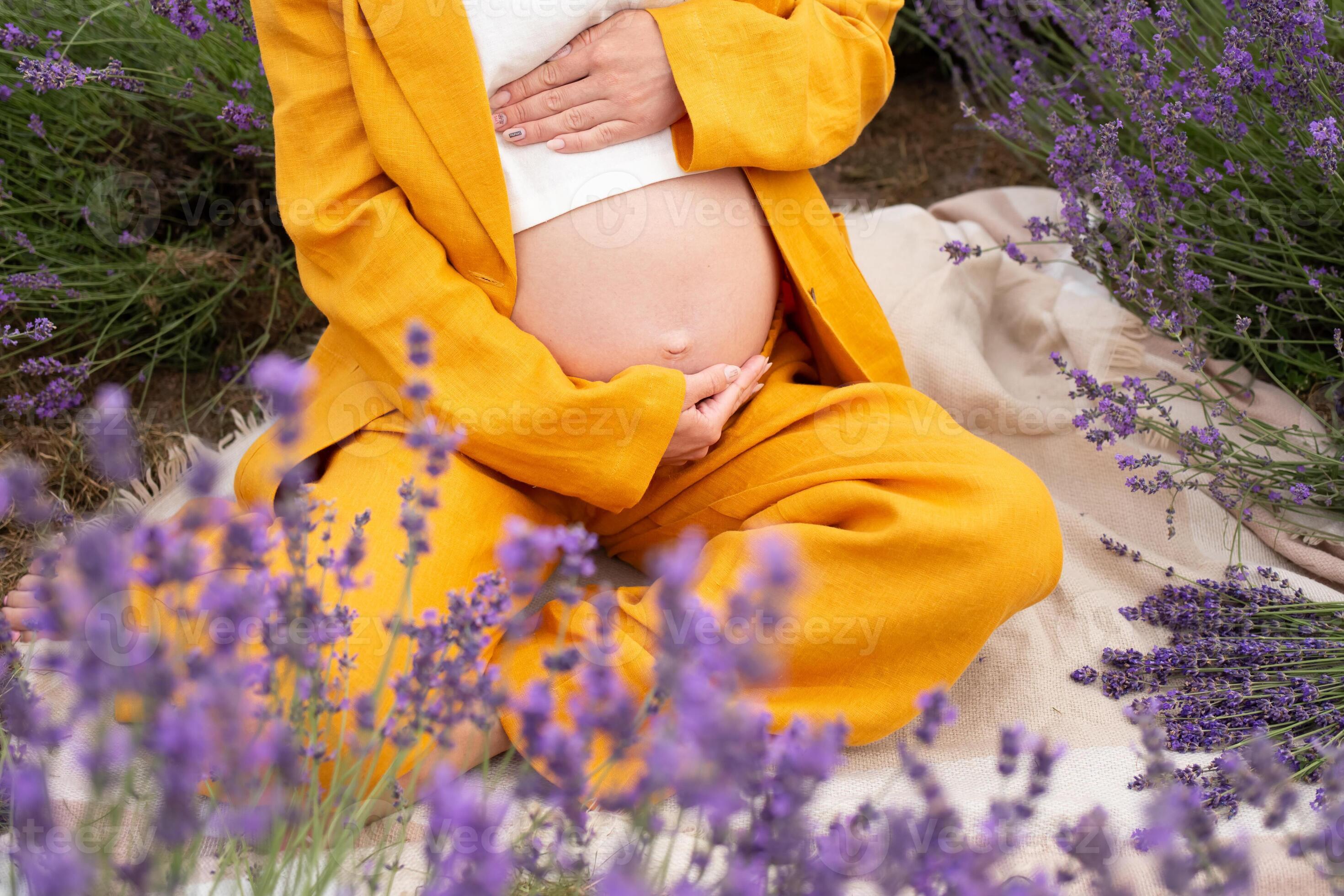 Pregnant Woman In A Beautiful Orange Suit Hugging Her Belly In A Field With Lavender Pregnancy