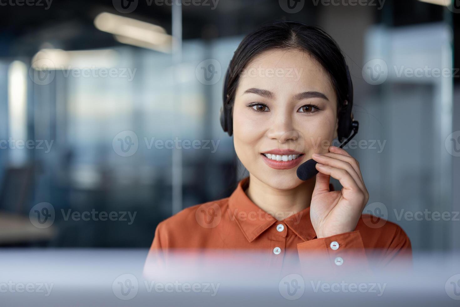 A cheerful Asian businesswoman wearing a headset, offering professional ... A cheerful Asian businesswoman wearing a headset, offering professional ...