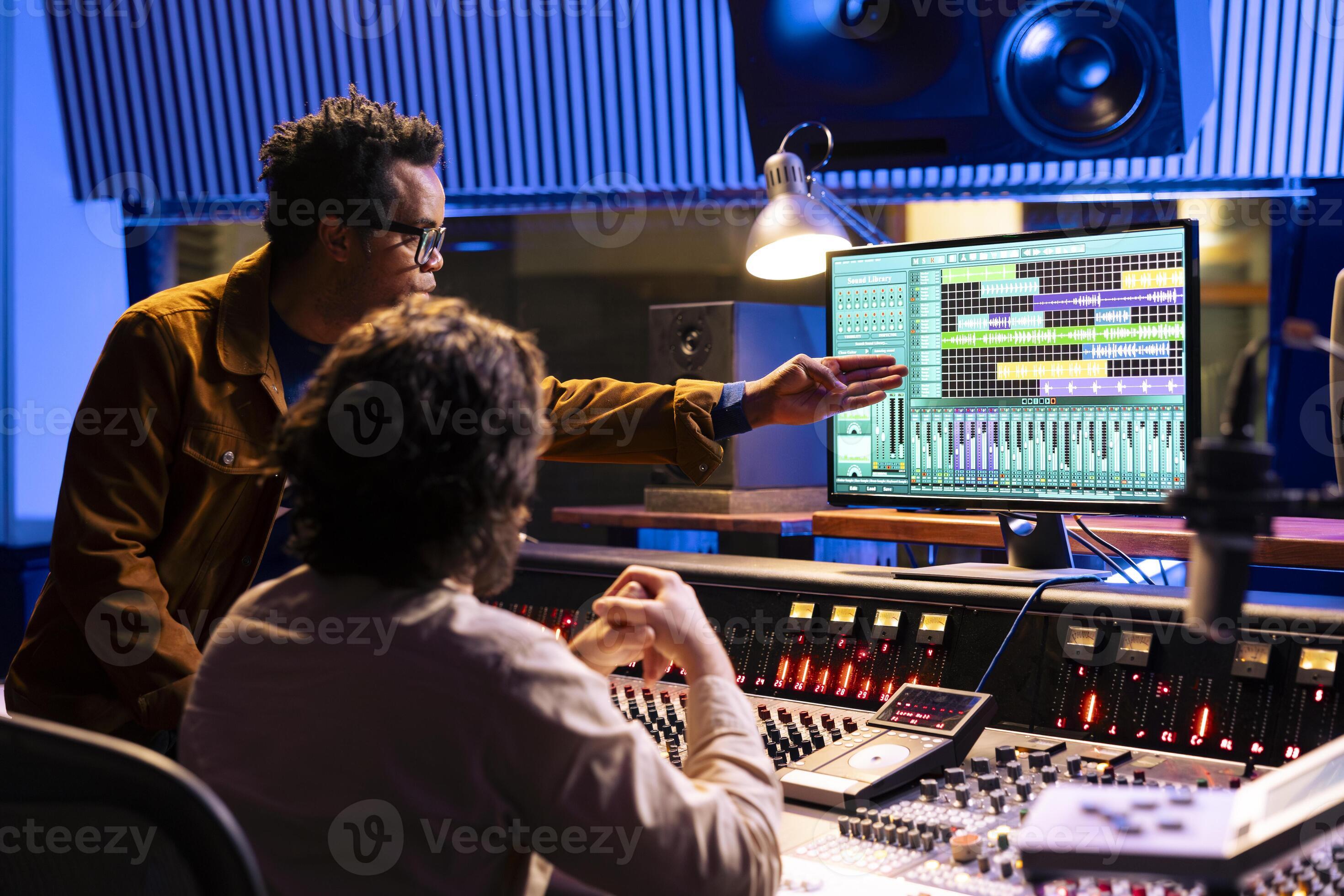 Diverse music experts mixing sounds on audio console and equalizer ...