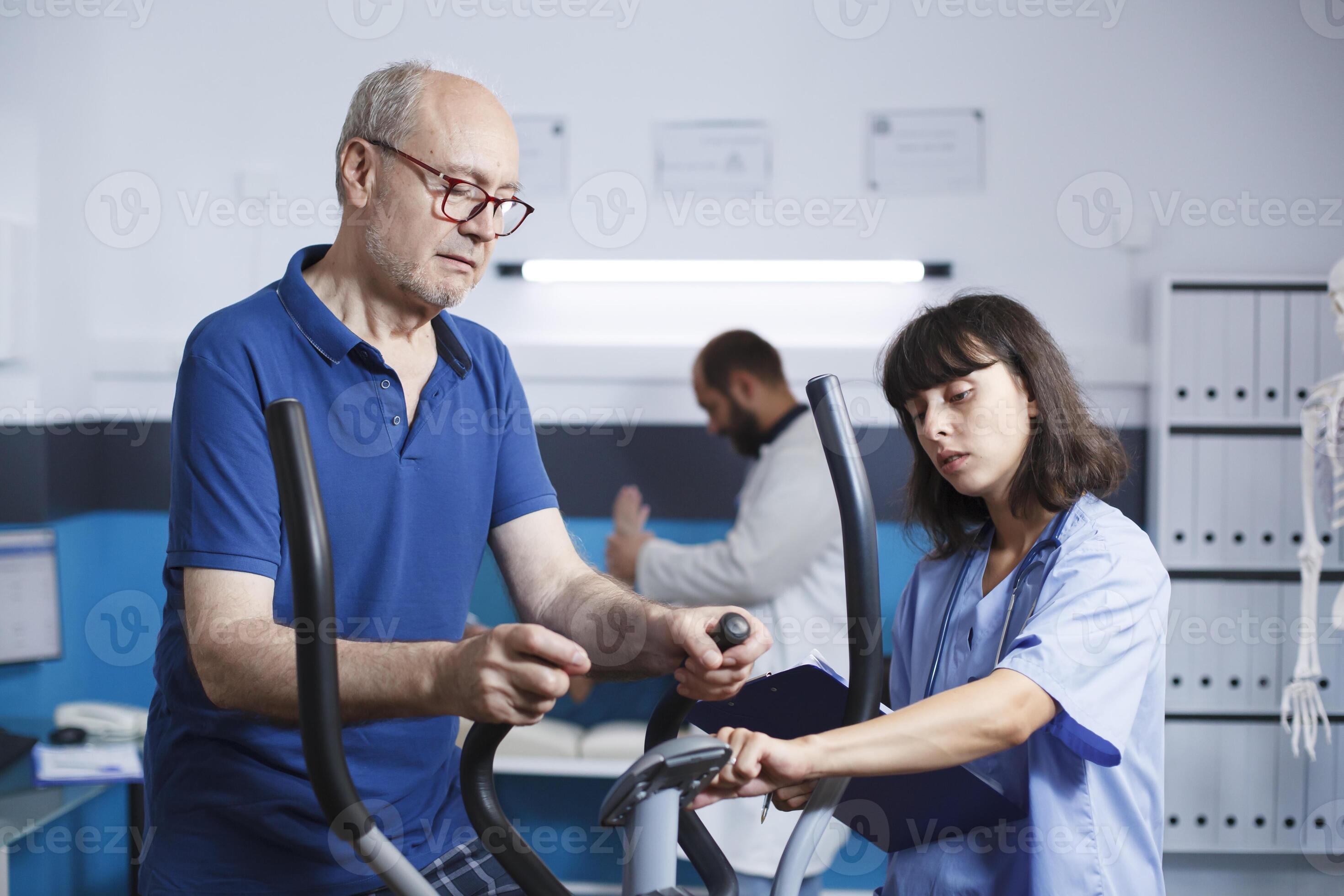 Senior male patient doing physical exercise for injury recovery with help from female nurse ...