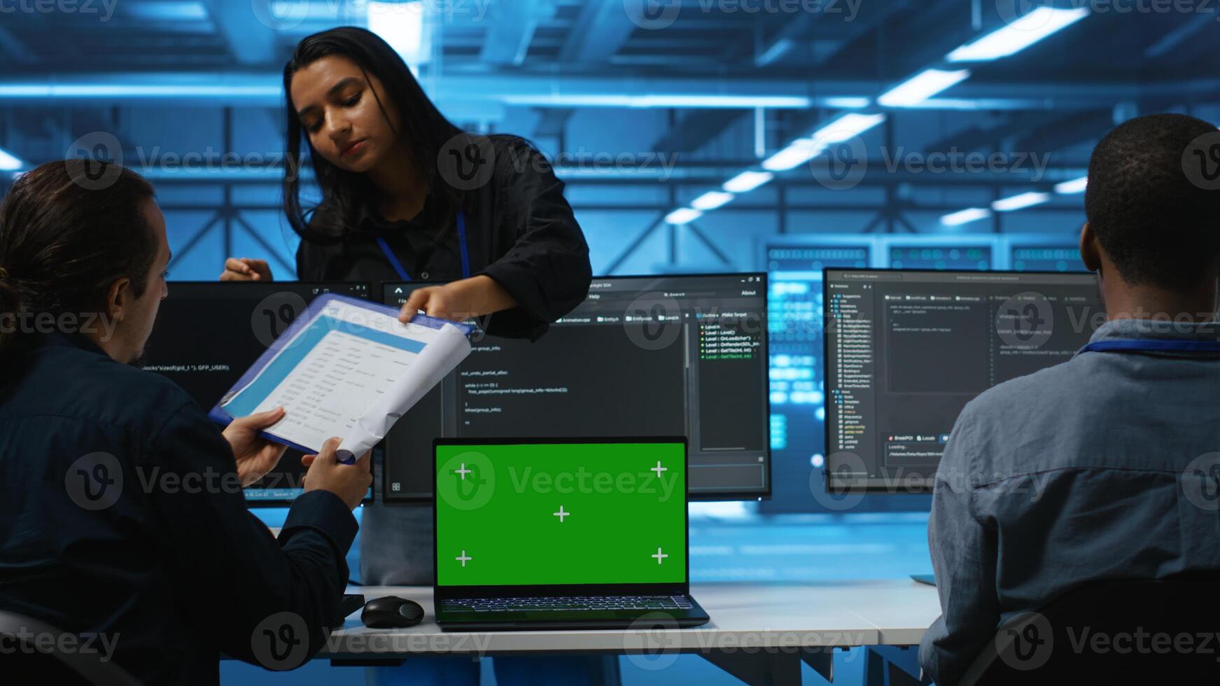 Green screen laptop in data center in front of manager and IT support specialists working ...